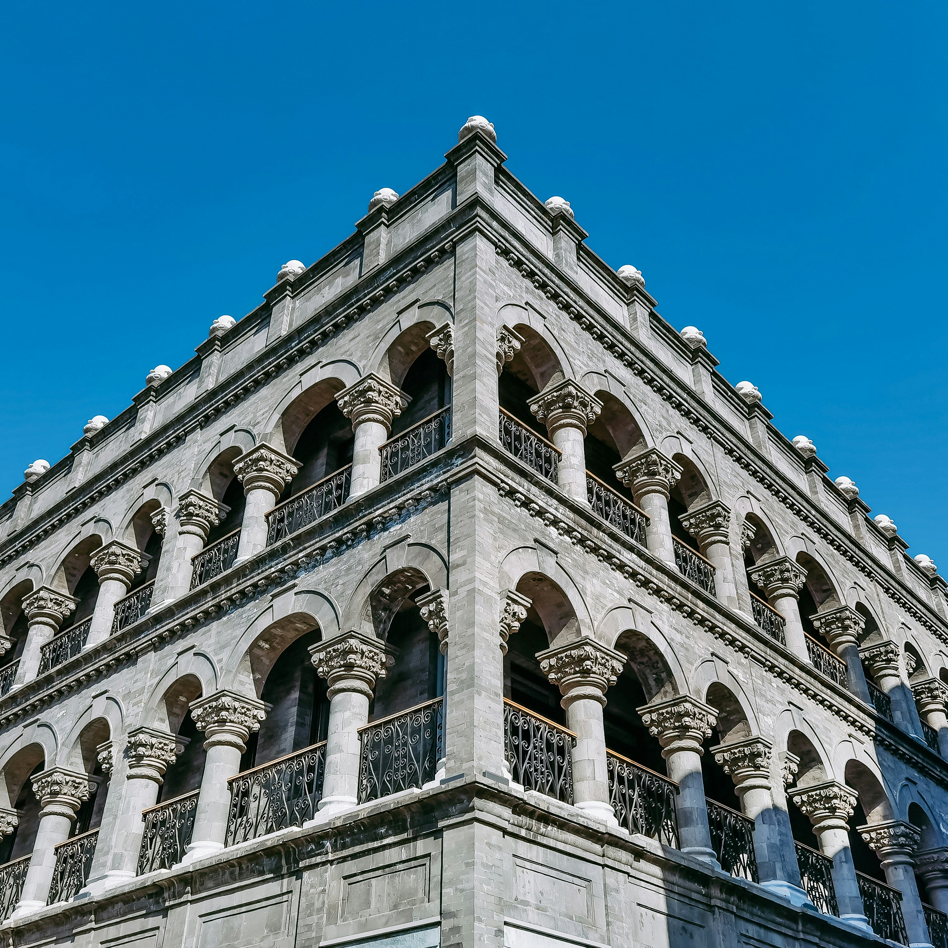 Intricate façade of a historic building featuring arched windows and ornate balconies against a clear blue sky.