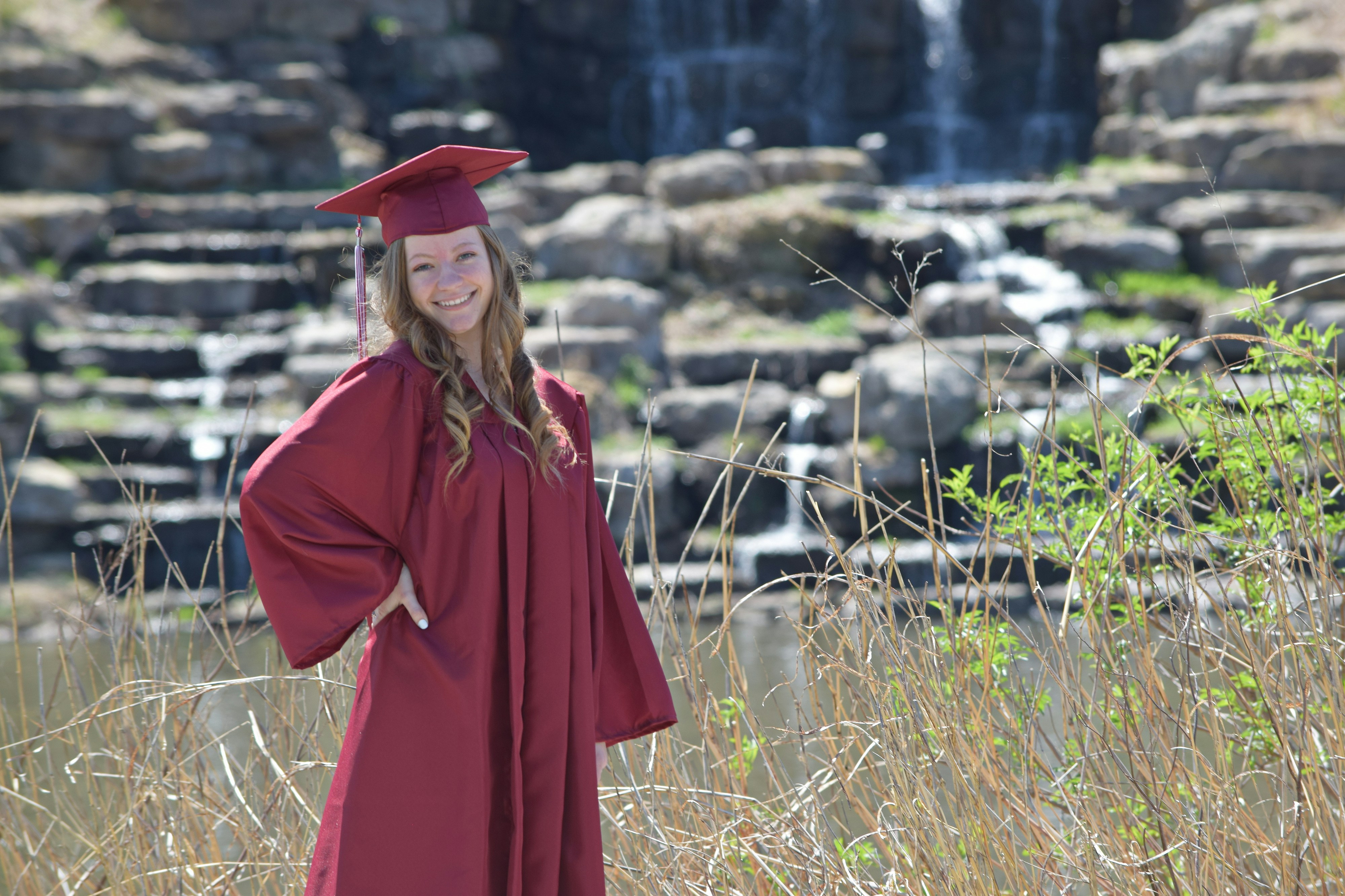 Woman in red academic dress standing on brown grass field during ...