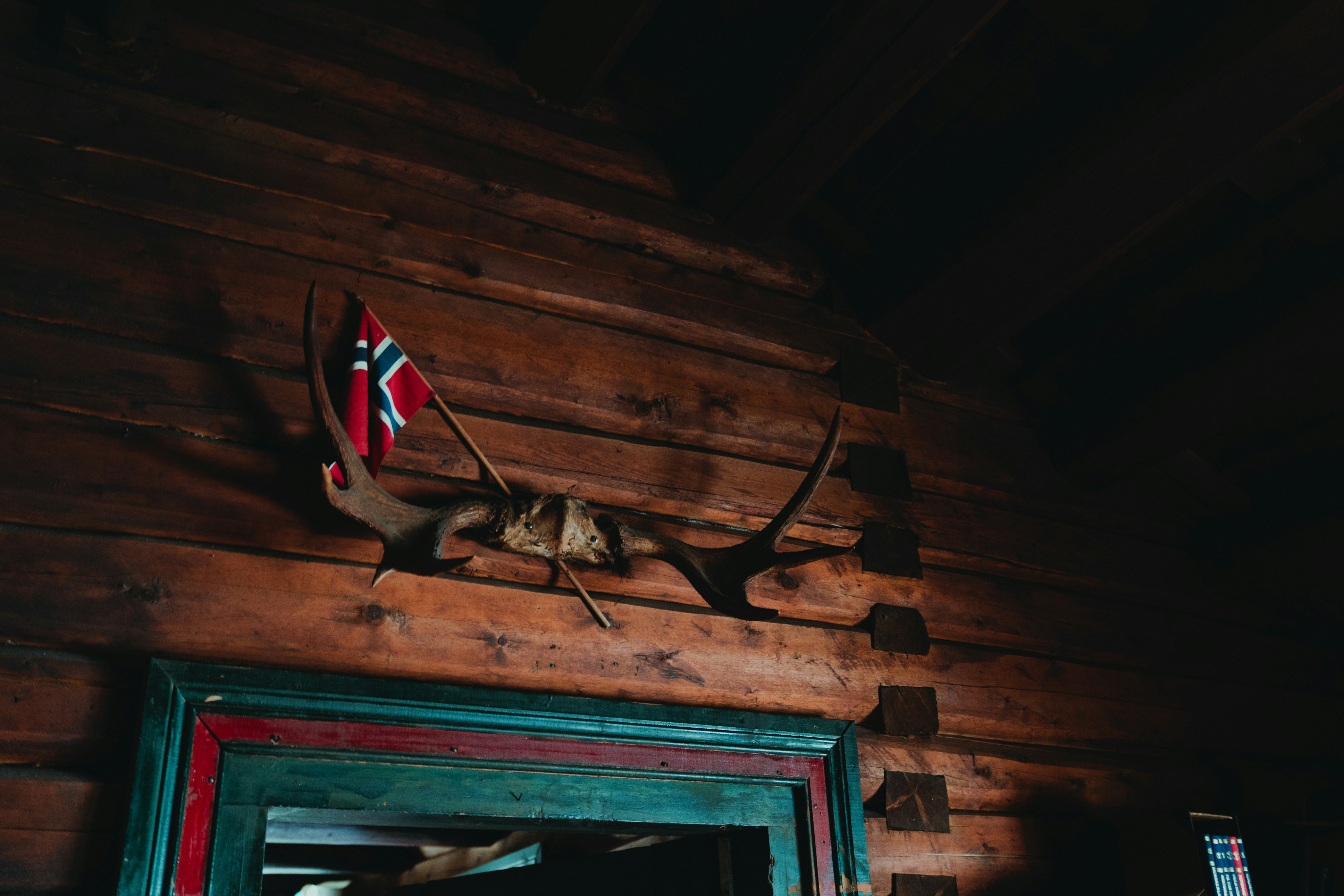 Nordic Stillness: Antlers, Flag, and Weathered Wood in a Dim Cabin