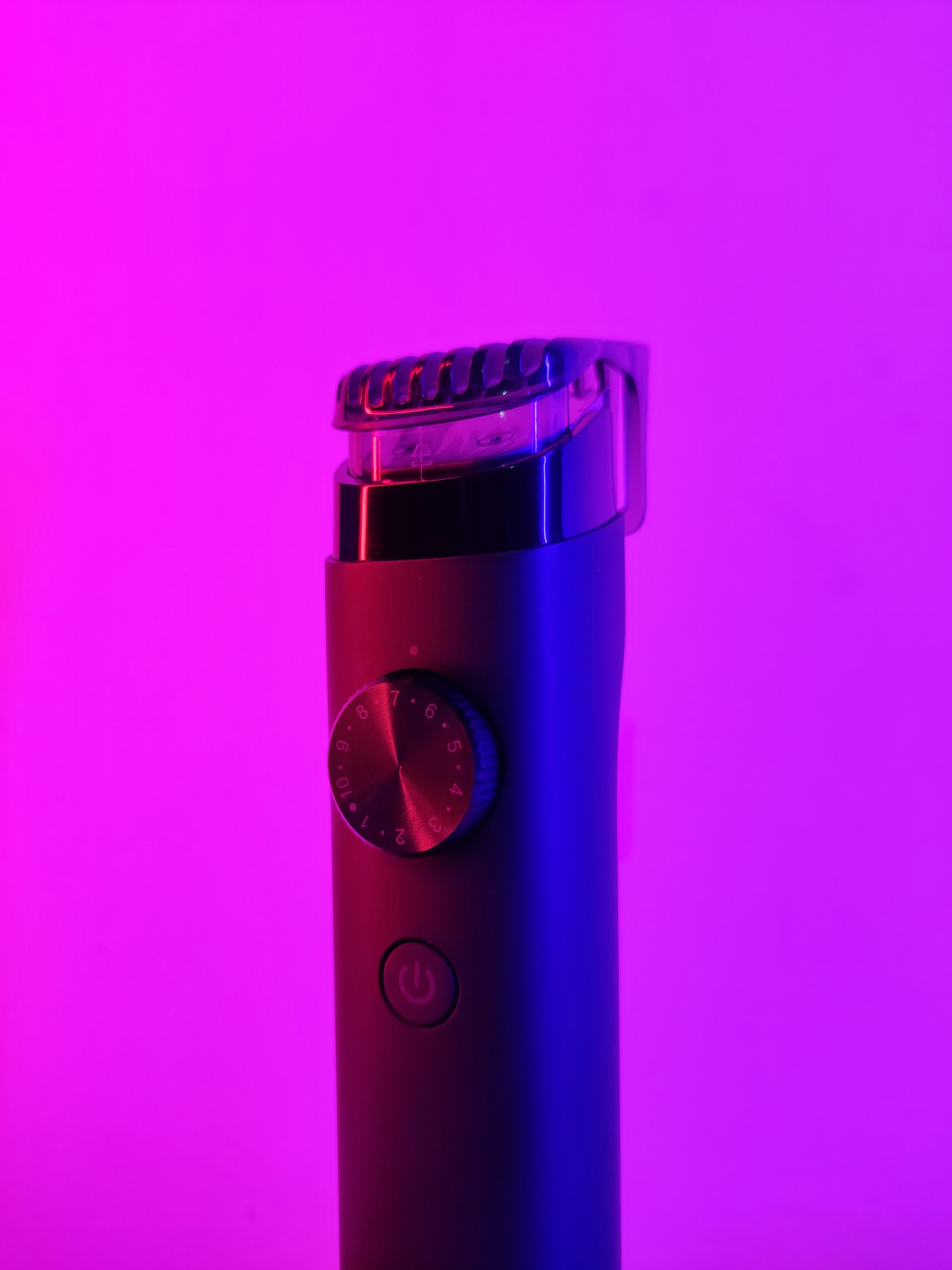 Electric trimmer against a vibrant purple backdrop, highlighting its sleek design and adjustable settings.