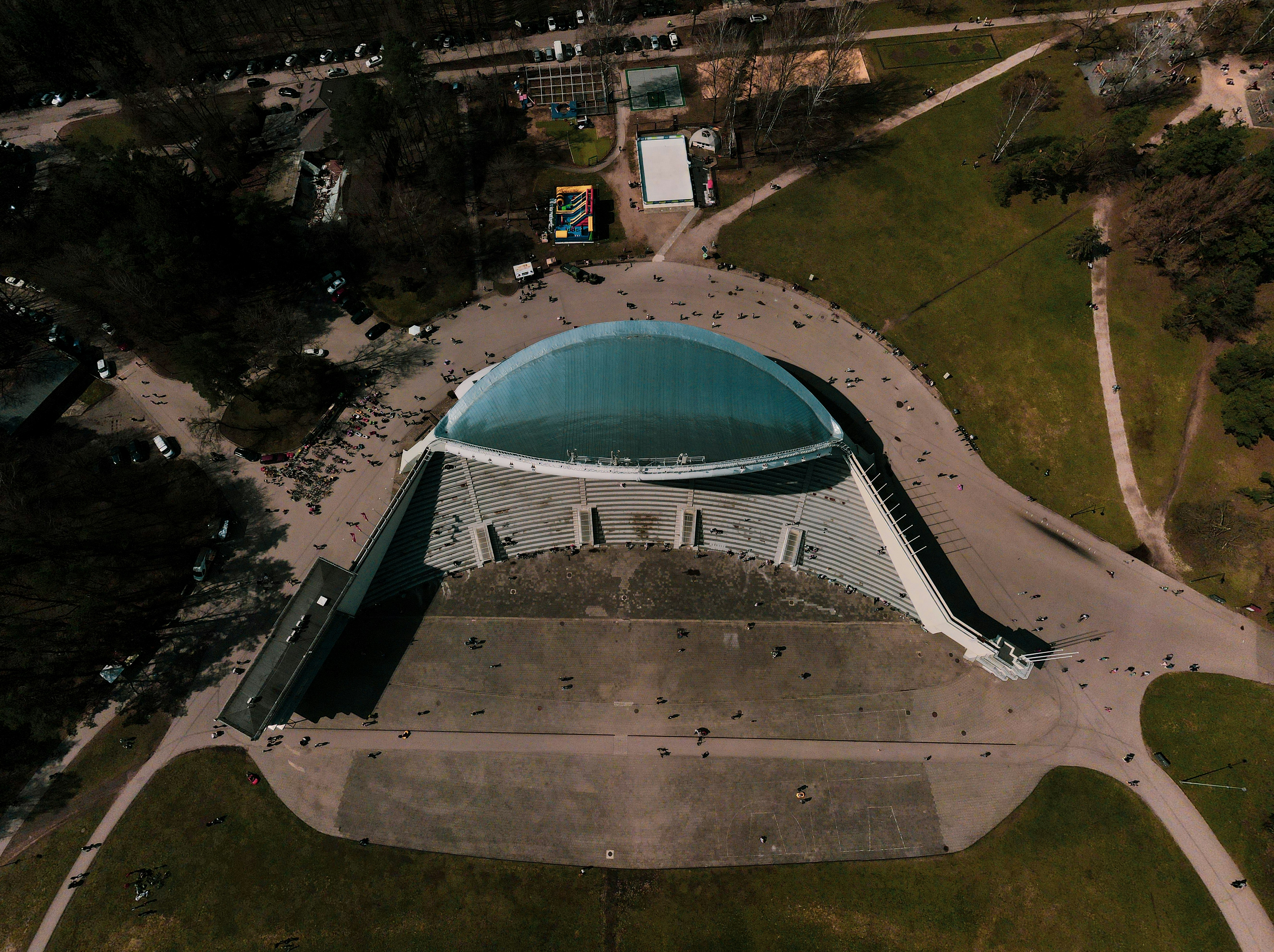 Aerial view of a blue-domed concert hall surrounded by lush greenery.