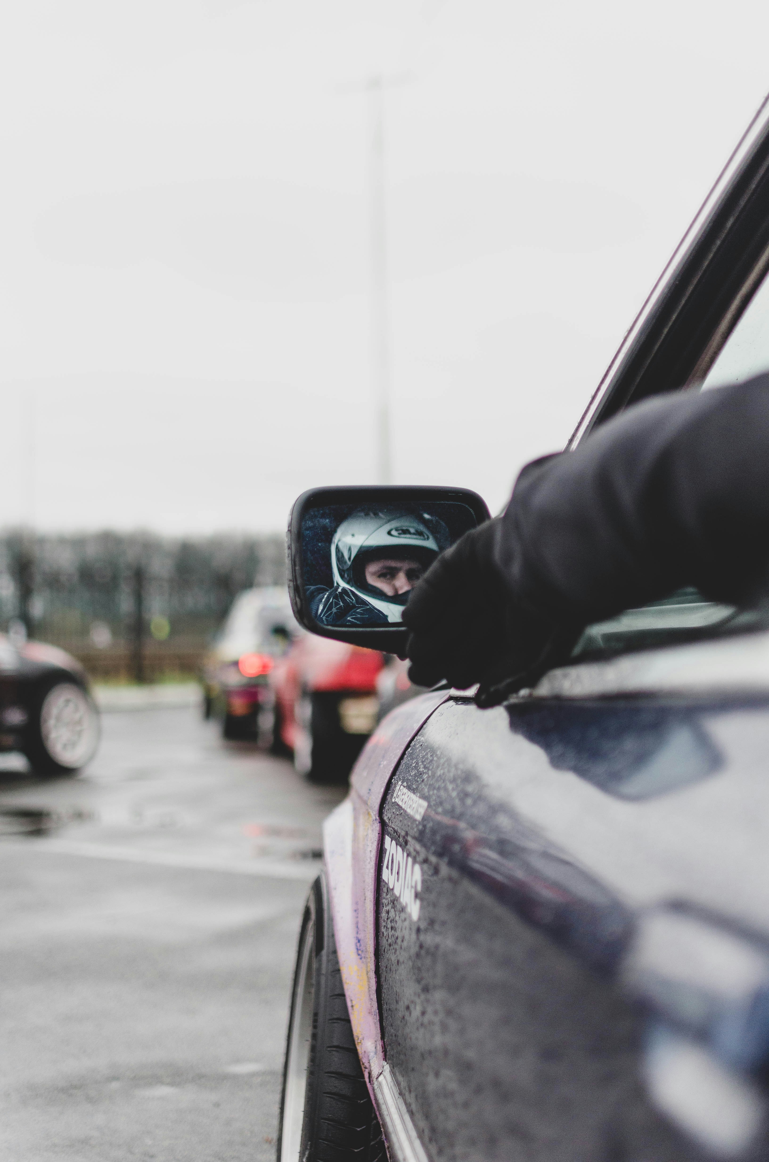 In-Transit Gaze: Helmeted Driver Reflected in a Car's Side Mirror