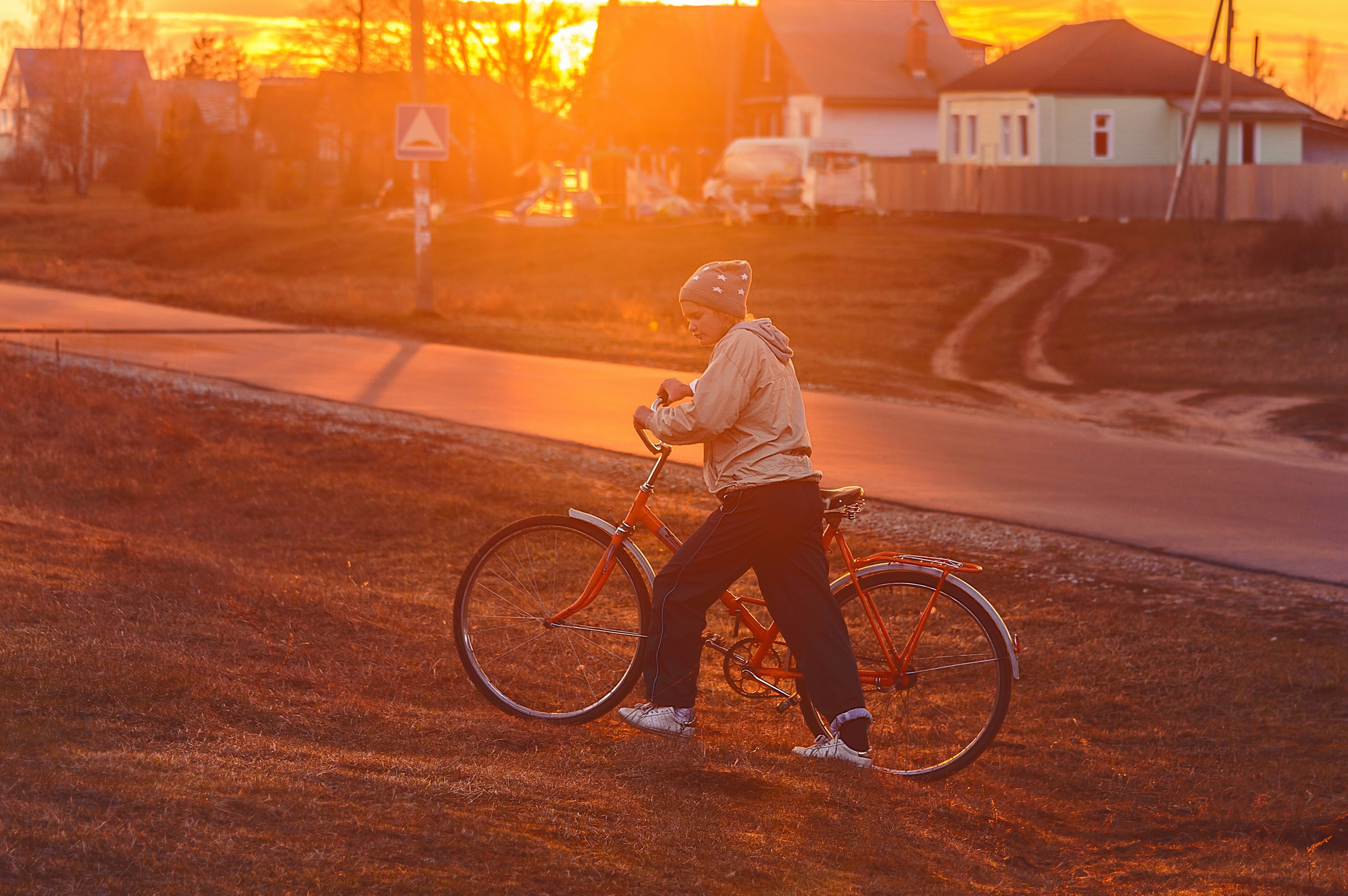 Ember Hour: A Person Walks a Bicycle Through Suburban Sunset