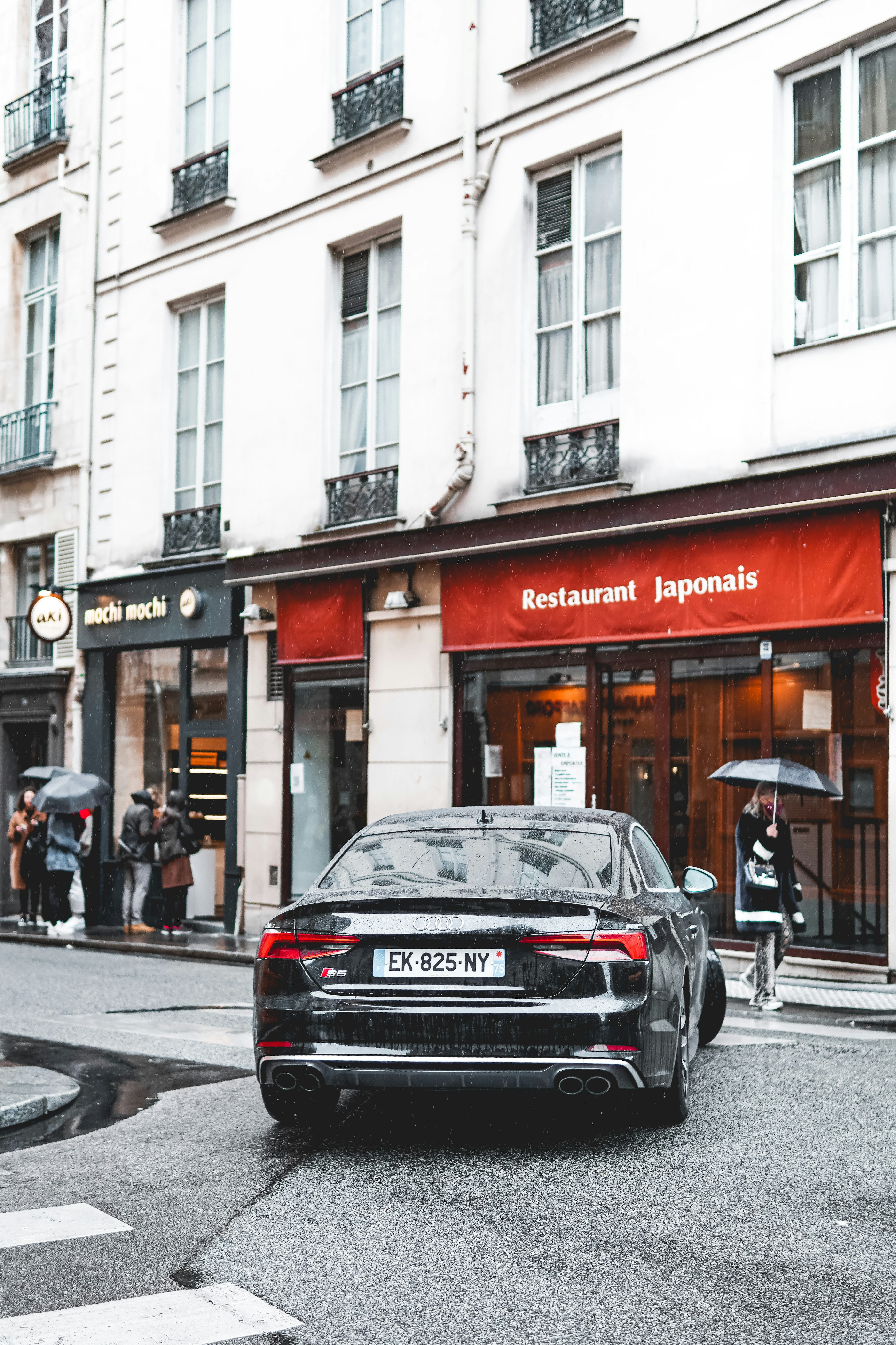 Street-side Bistro in the Rain: A Black Car in Front of a Japanese Restaurant