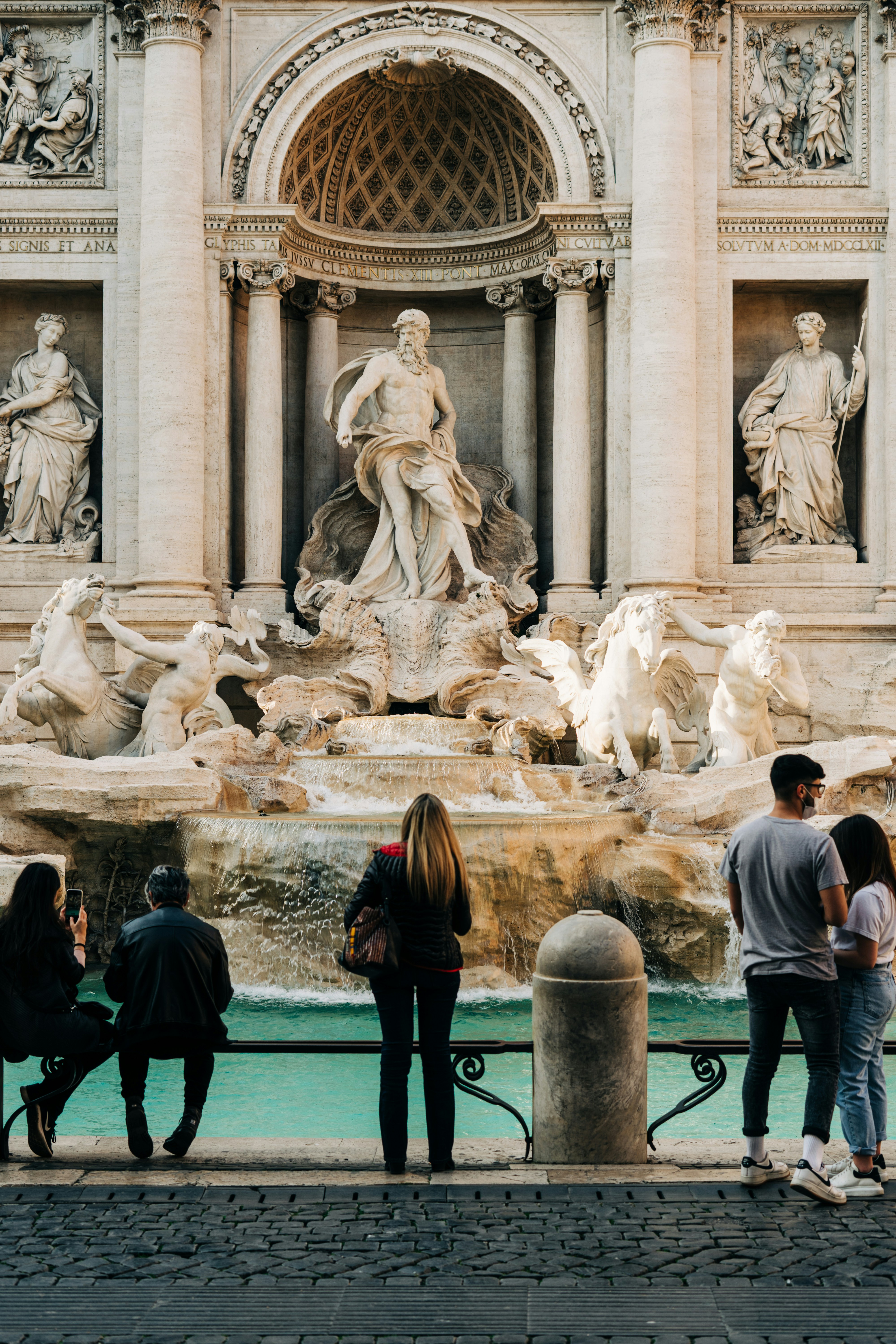 Visitors admire the majestic Trevi Fountain, featuring intricate sculptures and flowing water against a backdrop of classical architecture.