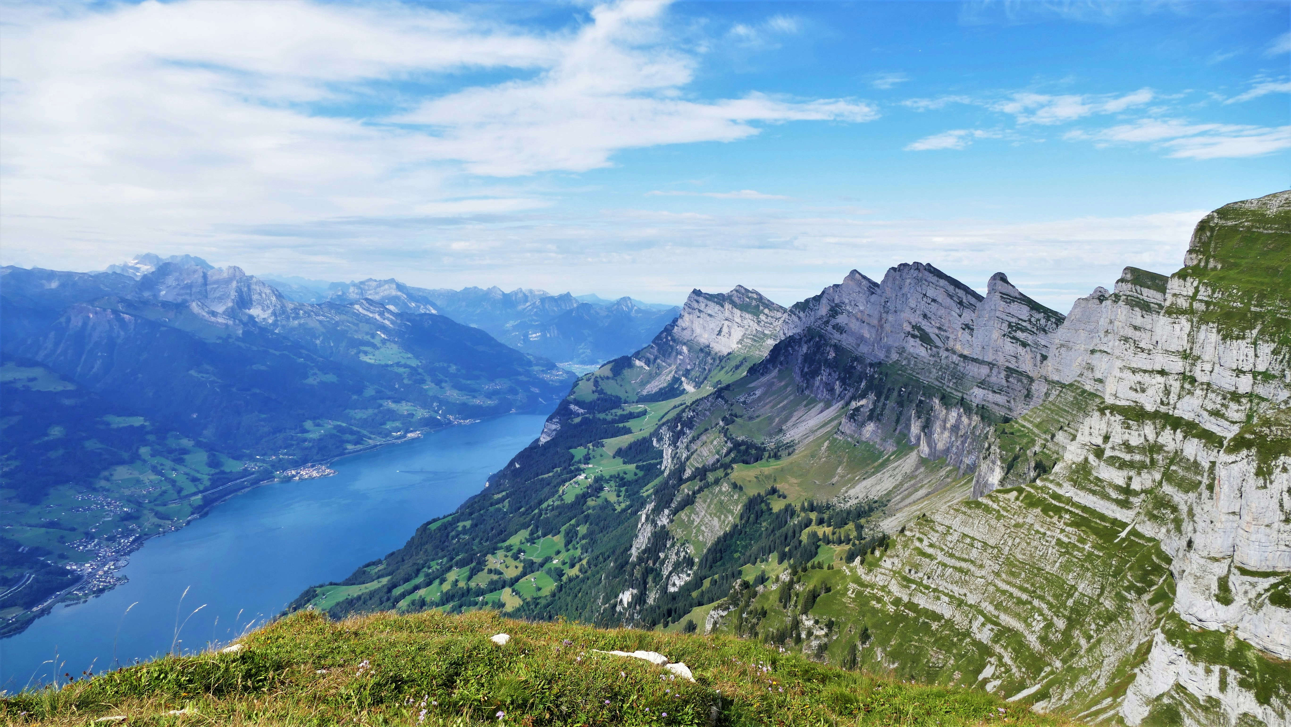 Vast mountain landscape with steep cliffs and a serene lake below, showcasing the beauty of the Swiss Alps.
