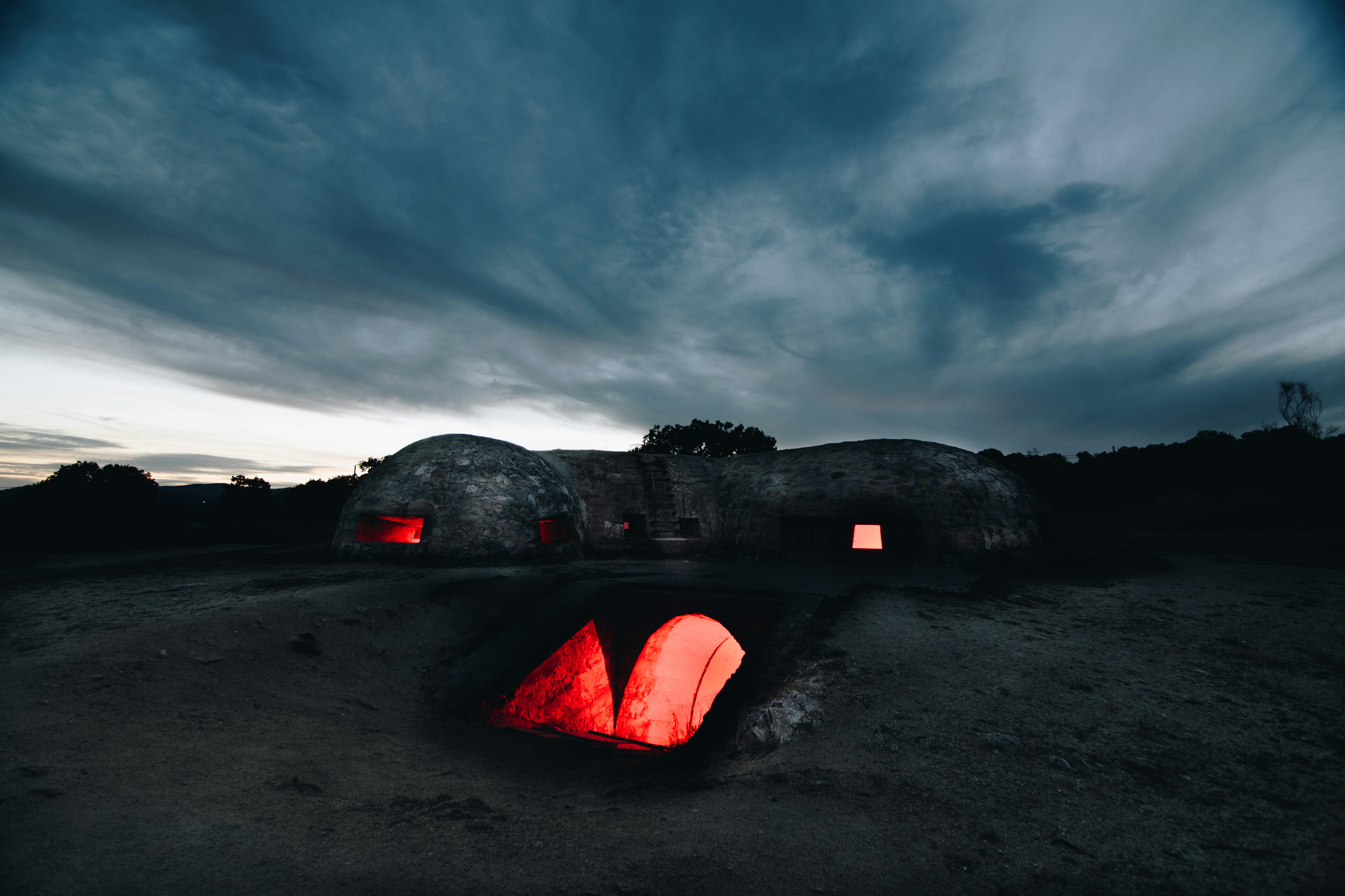 Glowing cave tents under a brooding dusk sky