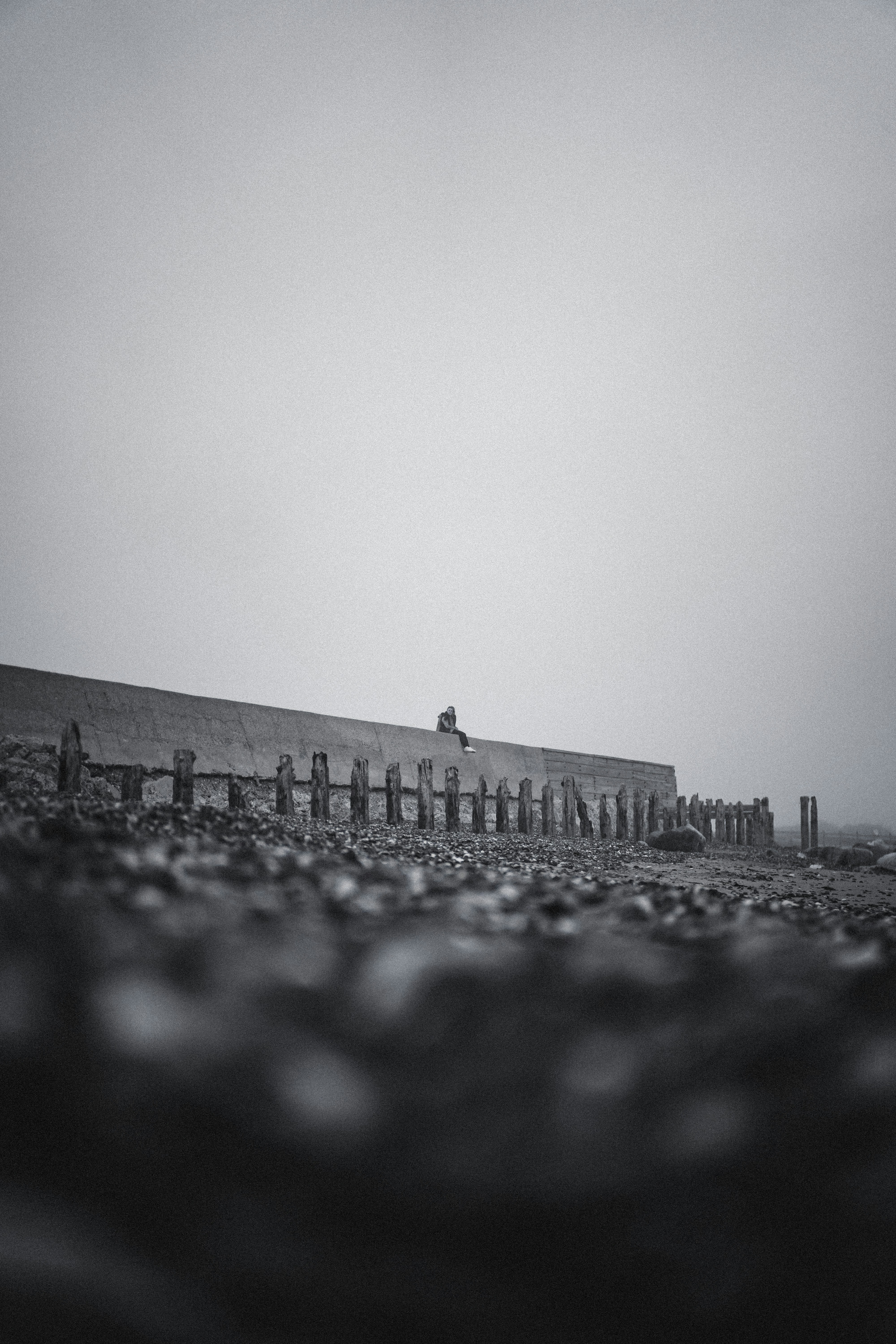 Silent Breakwater: A Lone Figure on the Pebble Shore