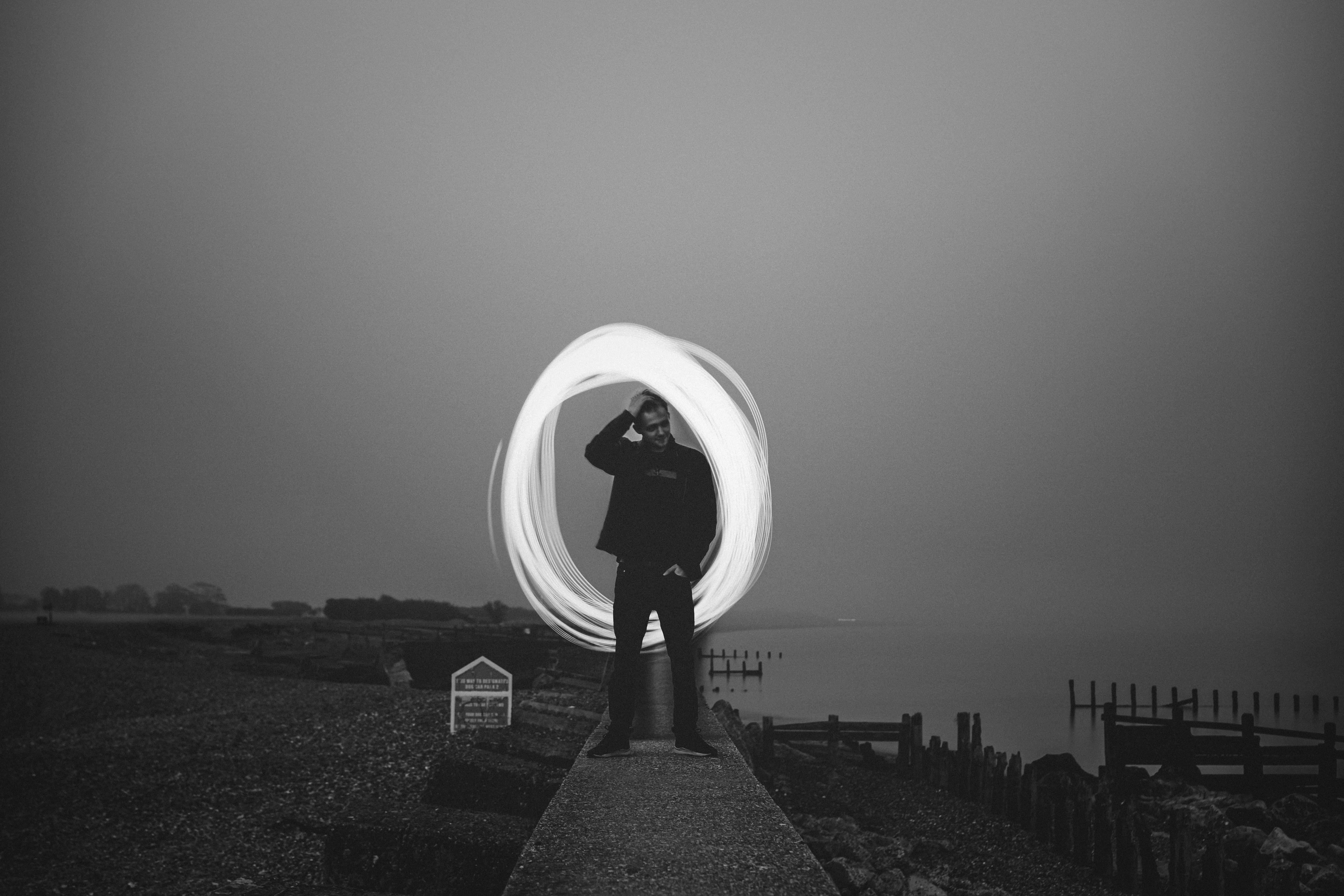 Ringed Silence: A Lone Figure on the Pier Encircled by Light