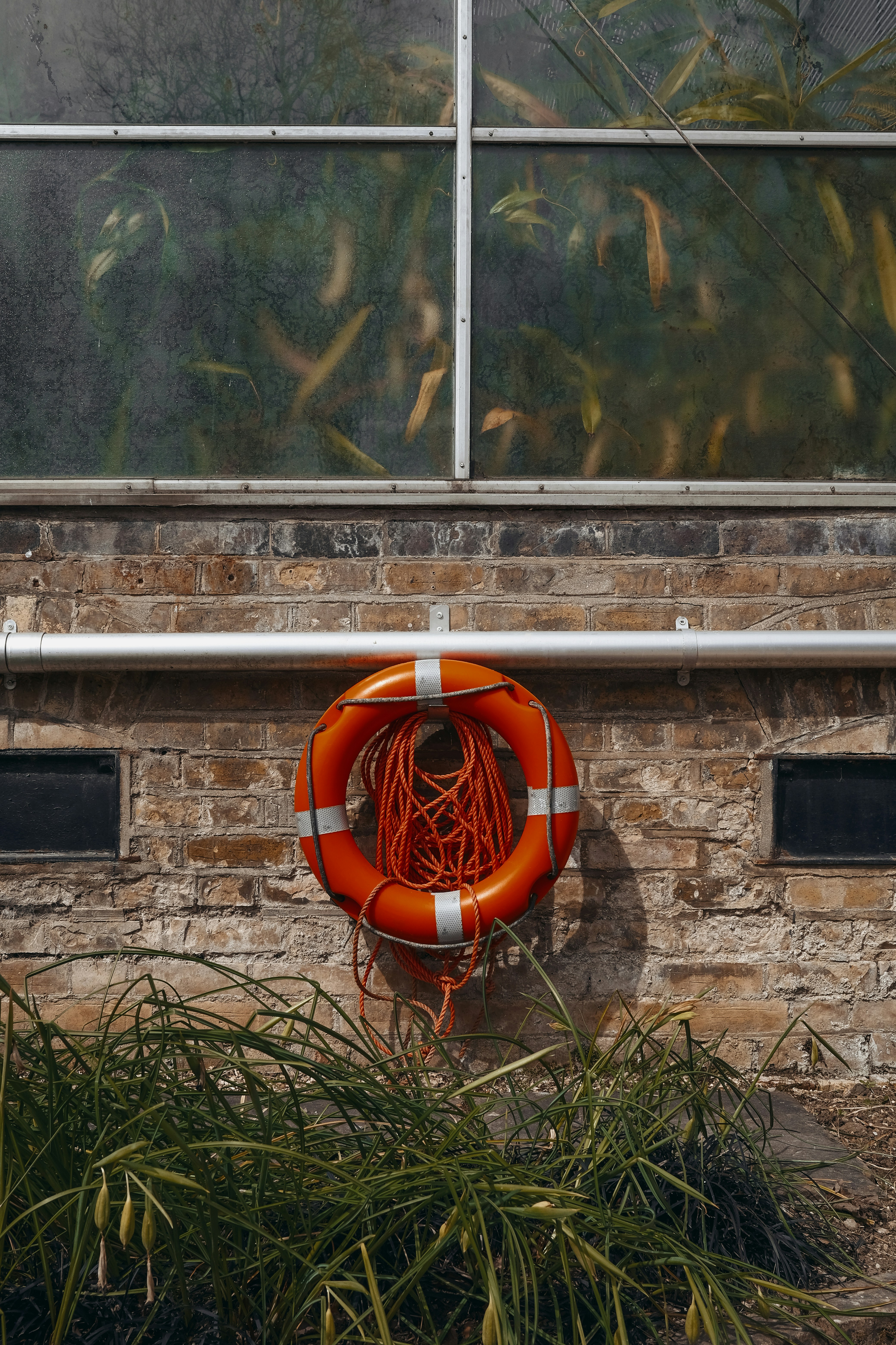 Lifebuoy at Rest: Orange Ring Against Weathered Brick Backdrop