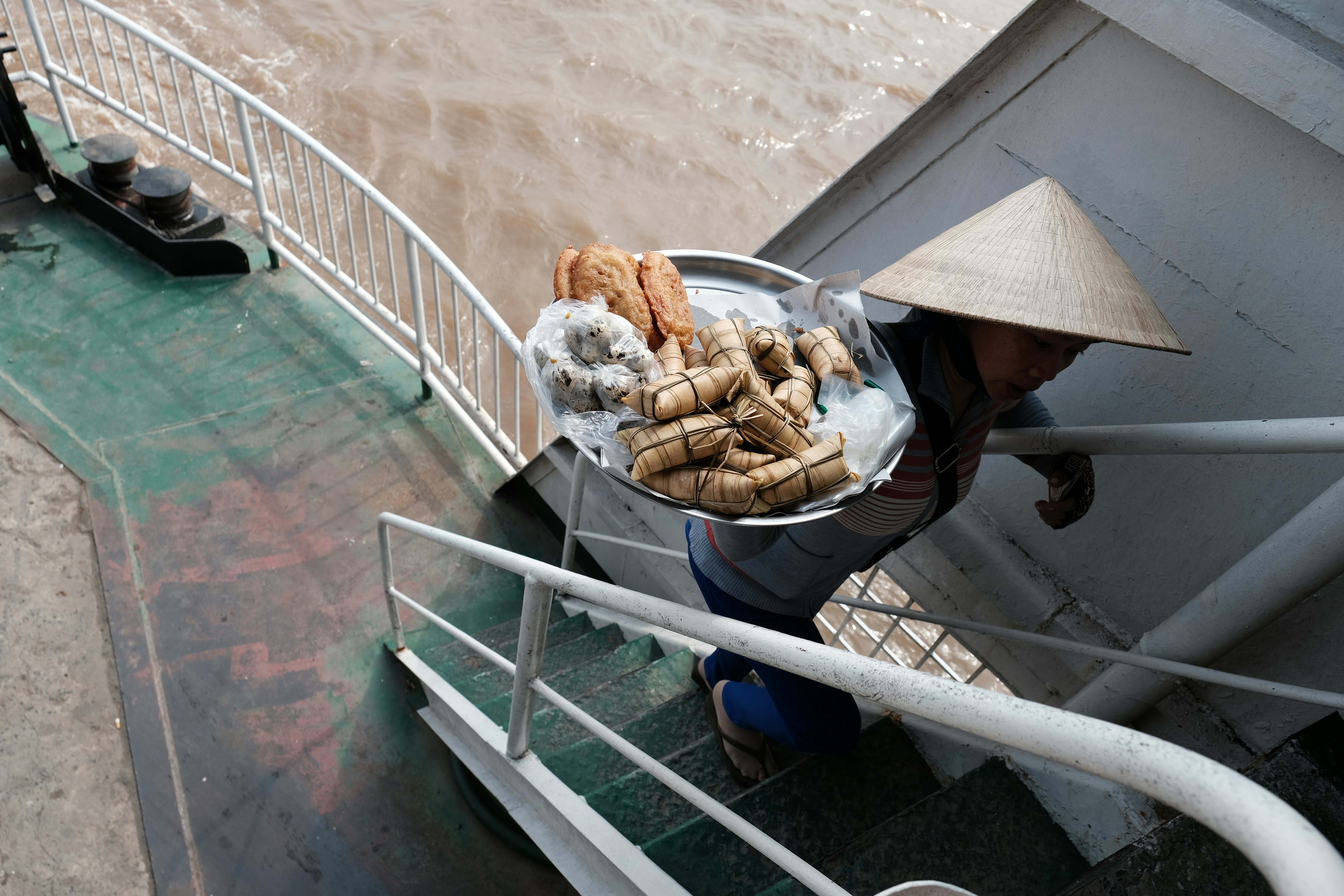 Conveyor of Treats: A Vendor Ascends the Stair with a Basket of Snacks