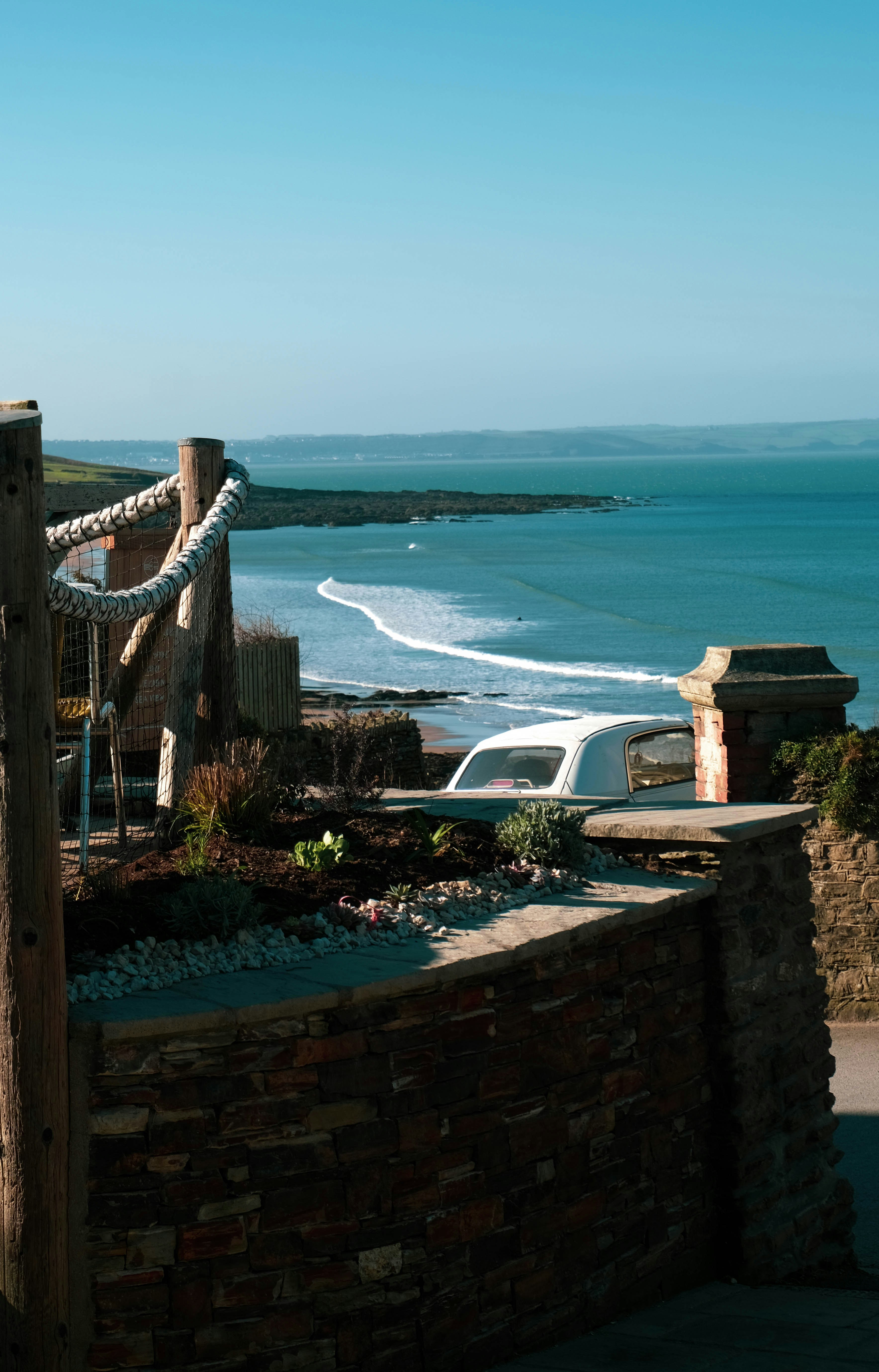 White Vintage Car Guarded by Stone Terrace Along a Coastal Walk