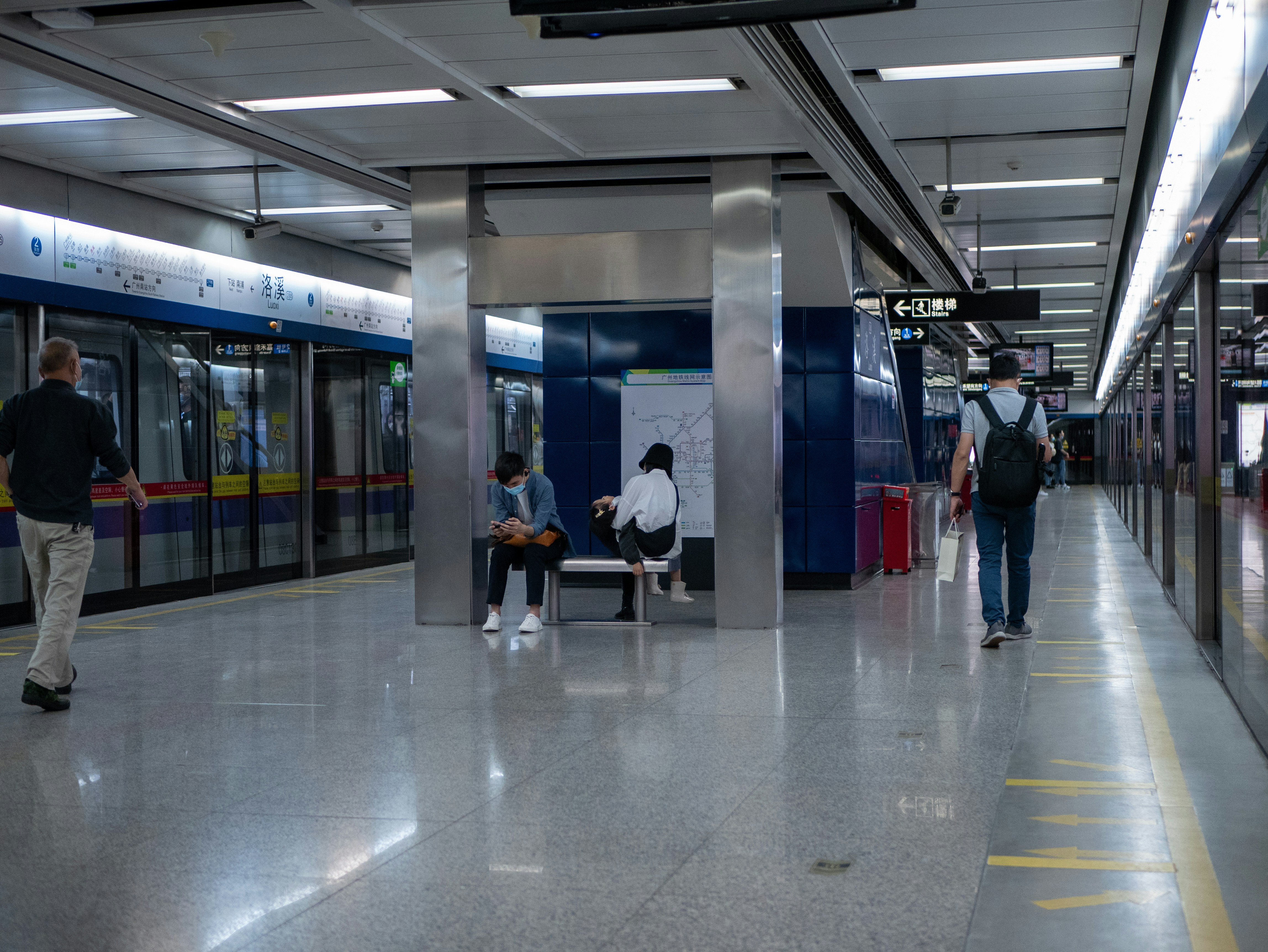 Mid-Platform Silence: Two Riders in a Blue-Tiled Subway Station