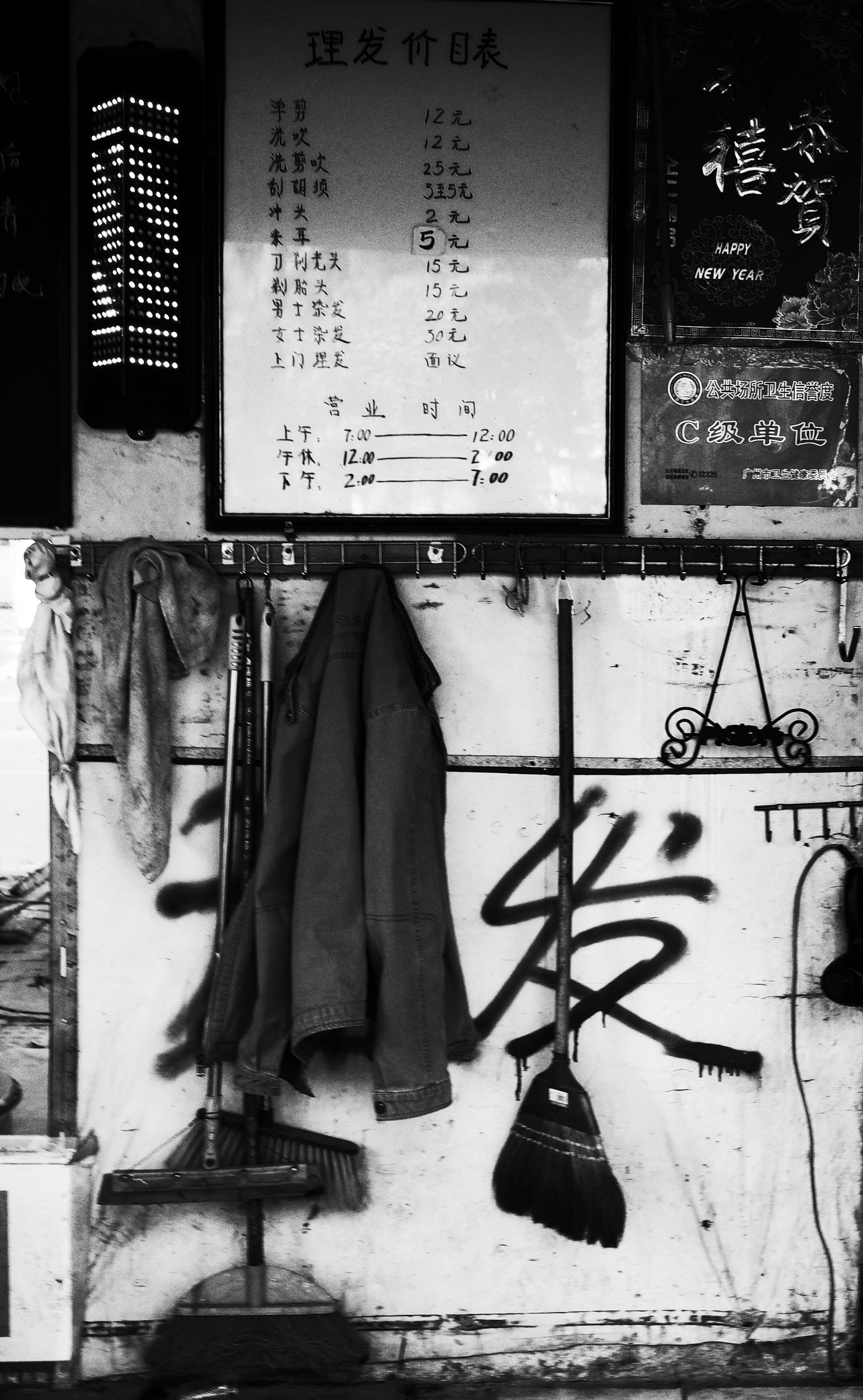 grayscale photo of man in jacket standing beside wall