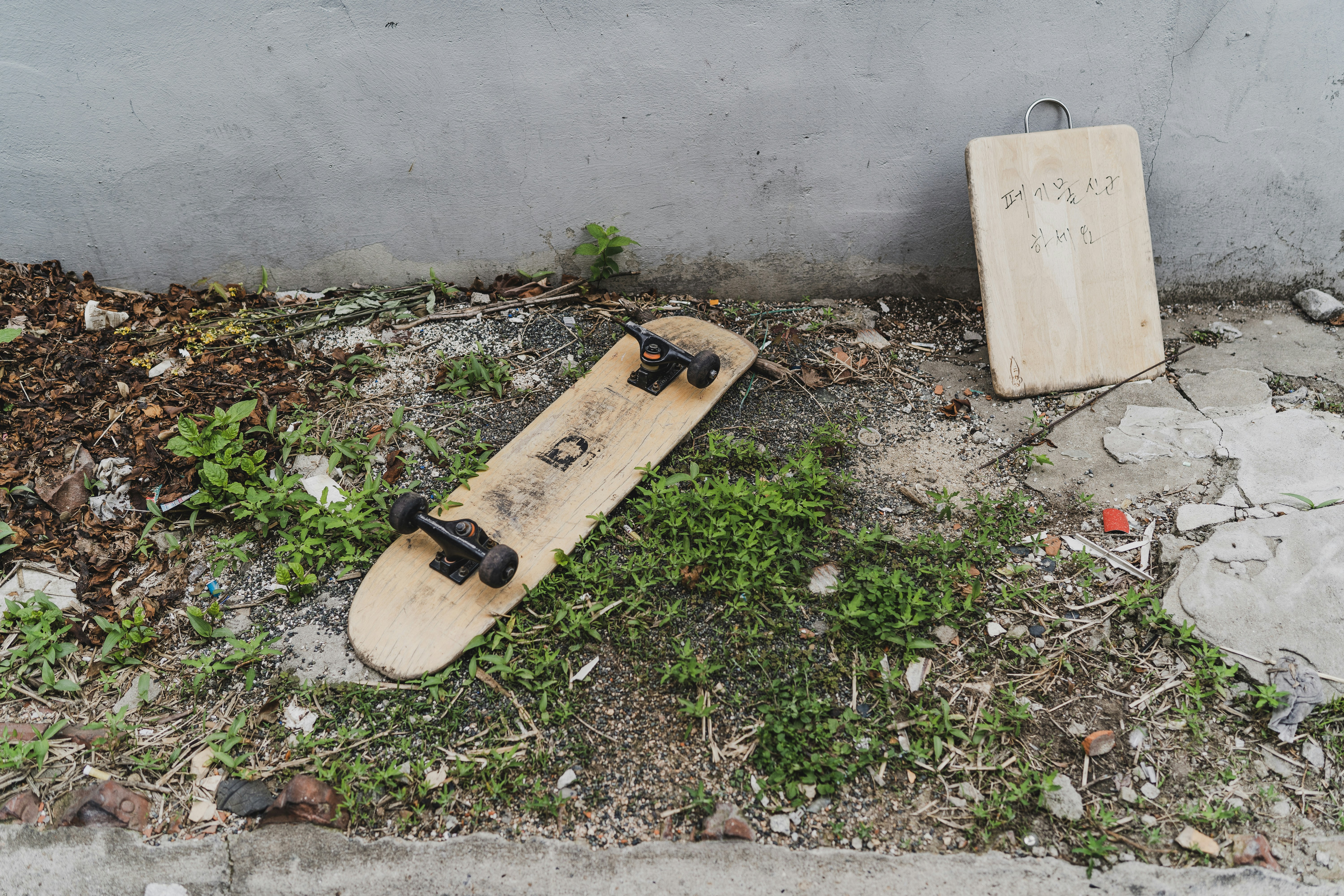 Weathered Longboard and Propped Cutting Board: A Quiet Curbside Study