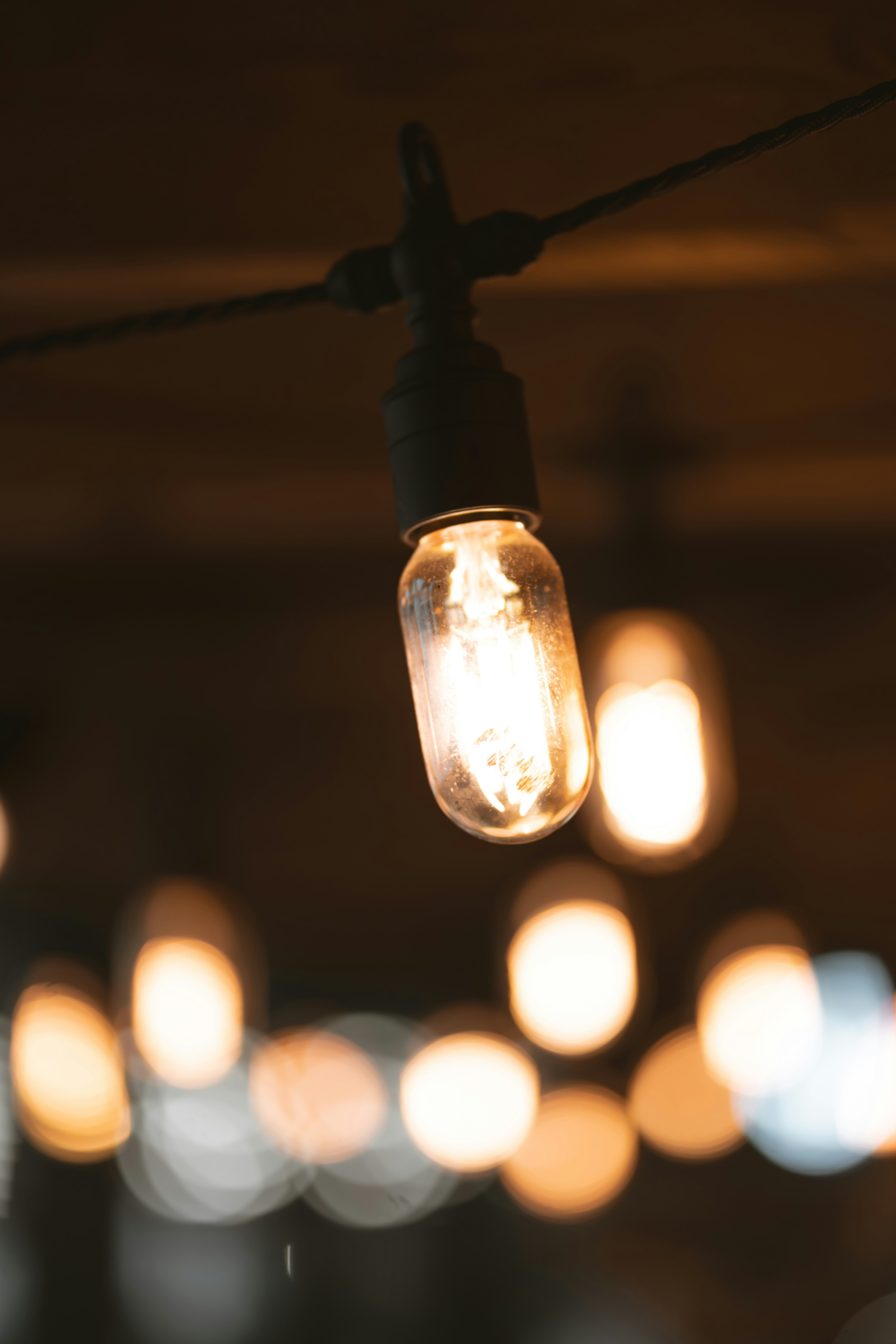 Vintage light bulb glowing softly against a blurred backdrop of warm bokeh lights. 
