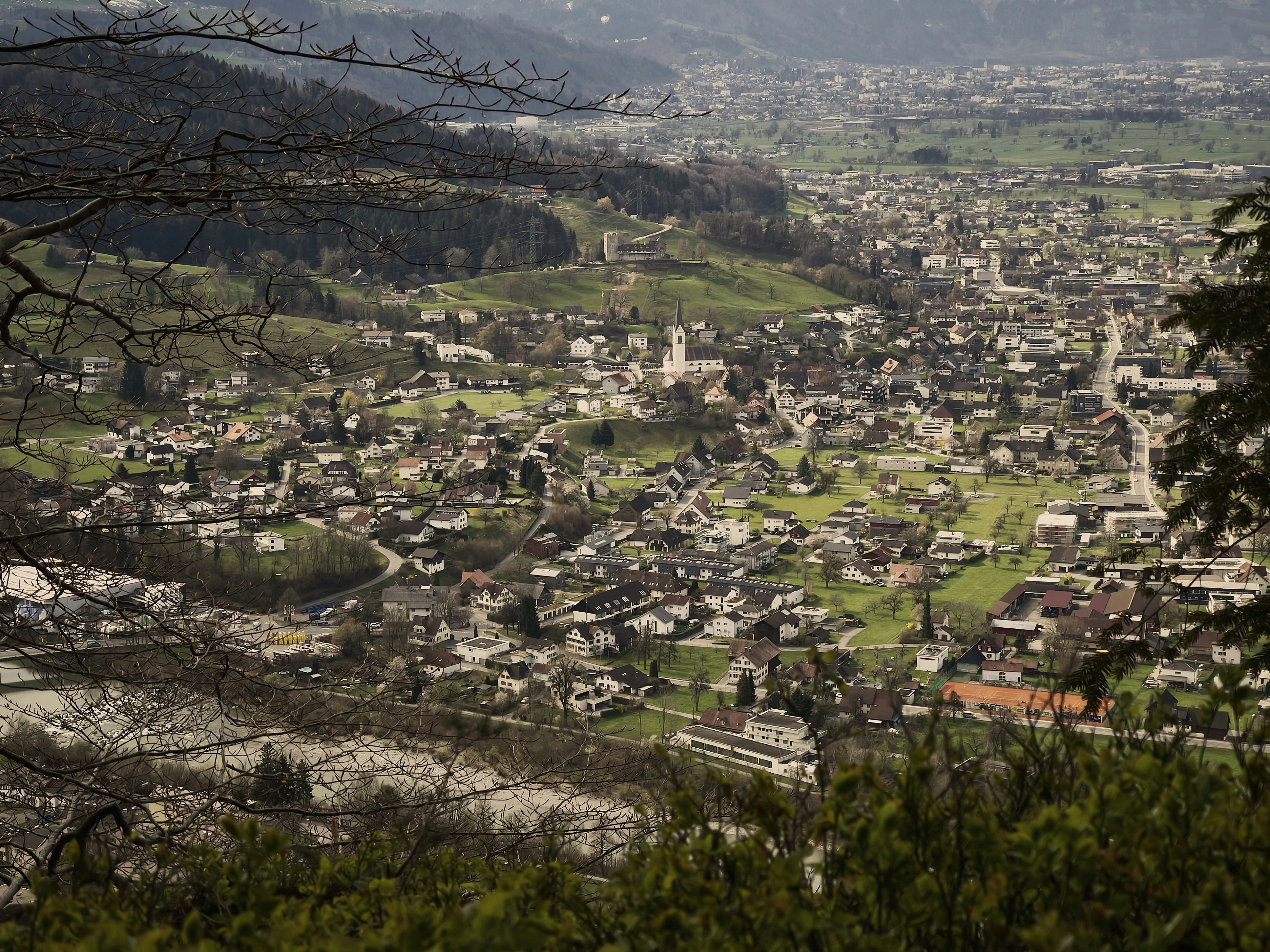 Expansive view of Wolfurt town nestled in a lush valley, surrounded by rolling hills.