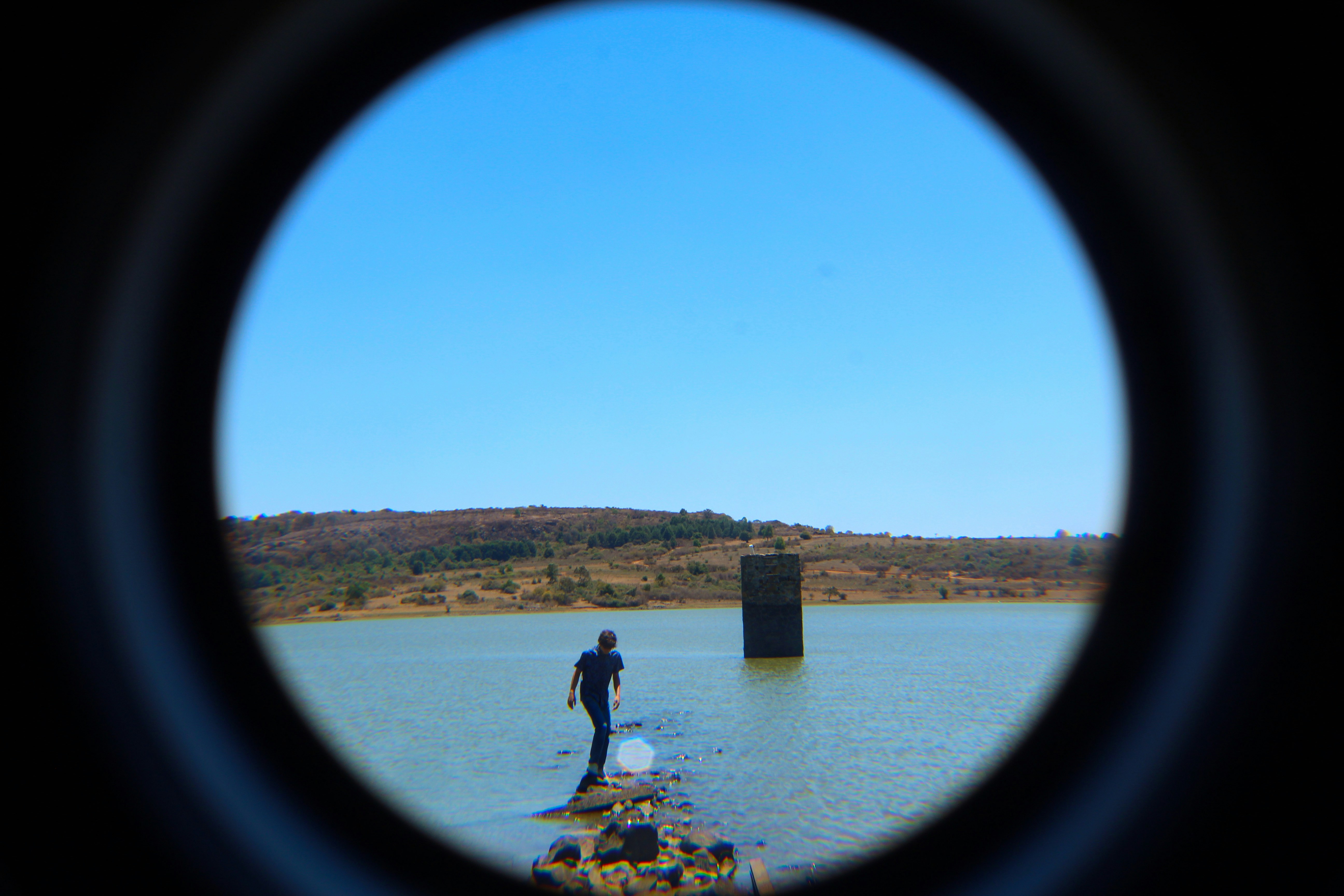 Through the Circular Frame: A Shoreline Trek Under a Clear Sky