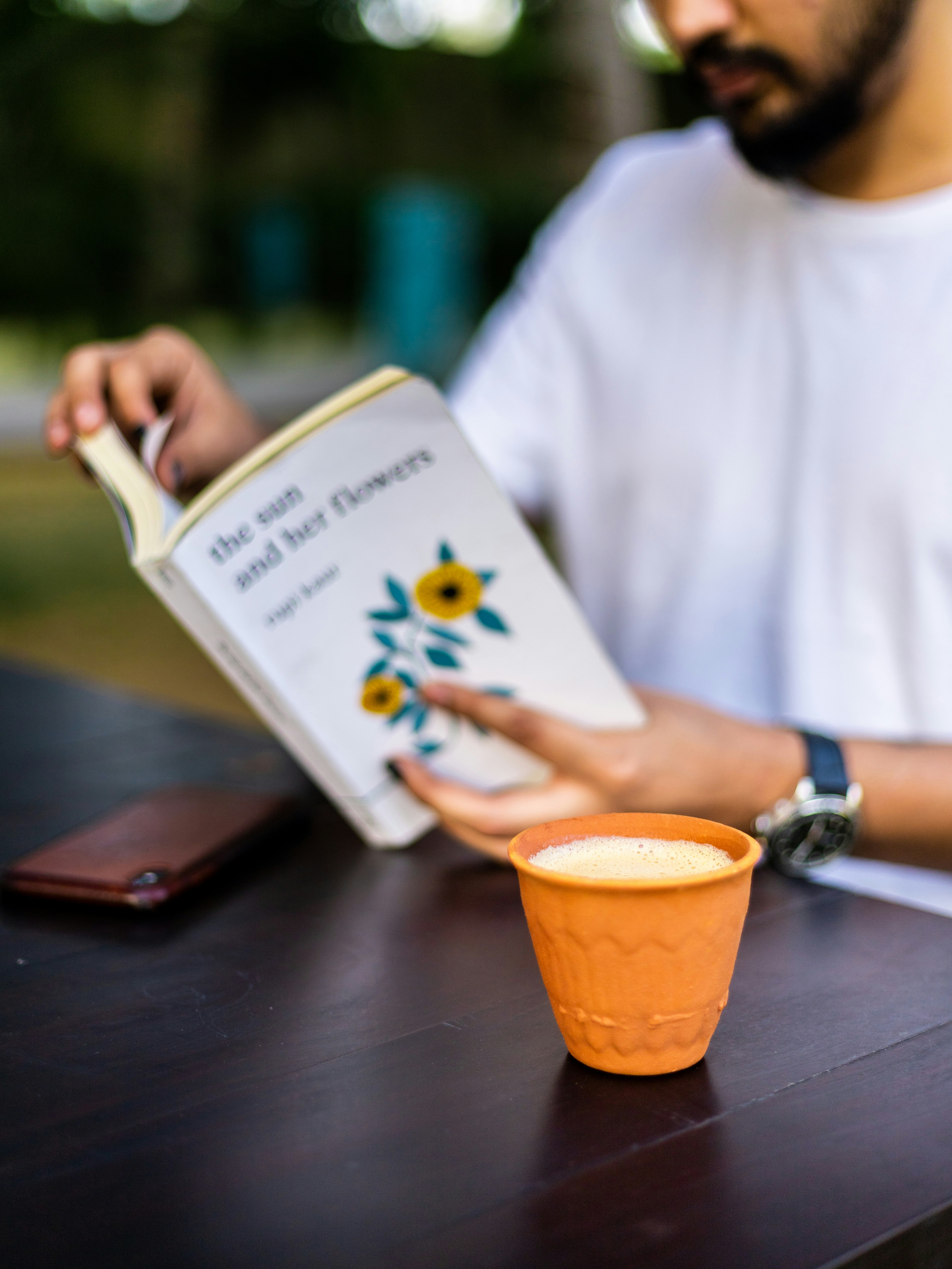 Irani Tea with person reading a book. | man in white crew neck t-shirt holding white book