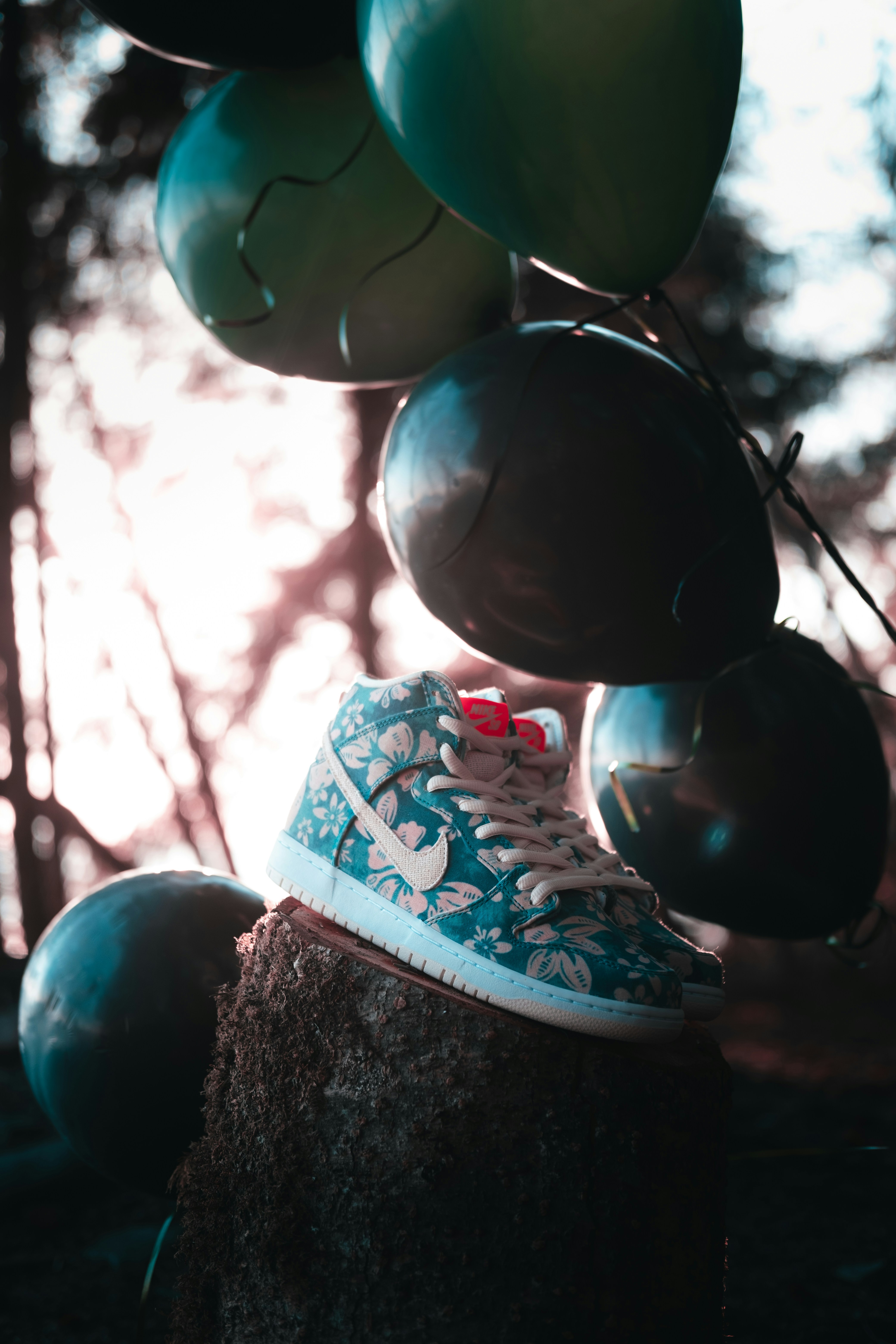 Floral sneaker on moss: balloons drift over a moody dusk backdrop
