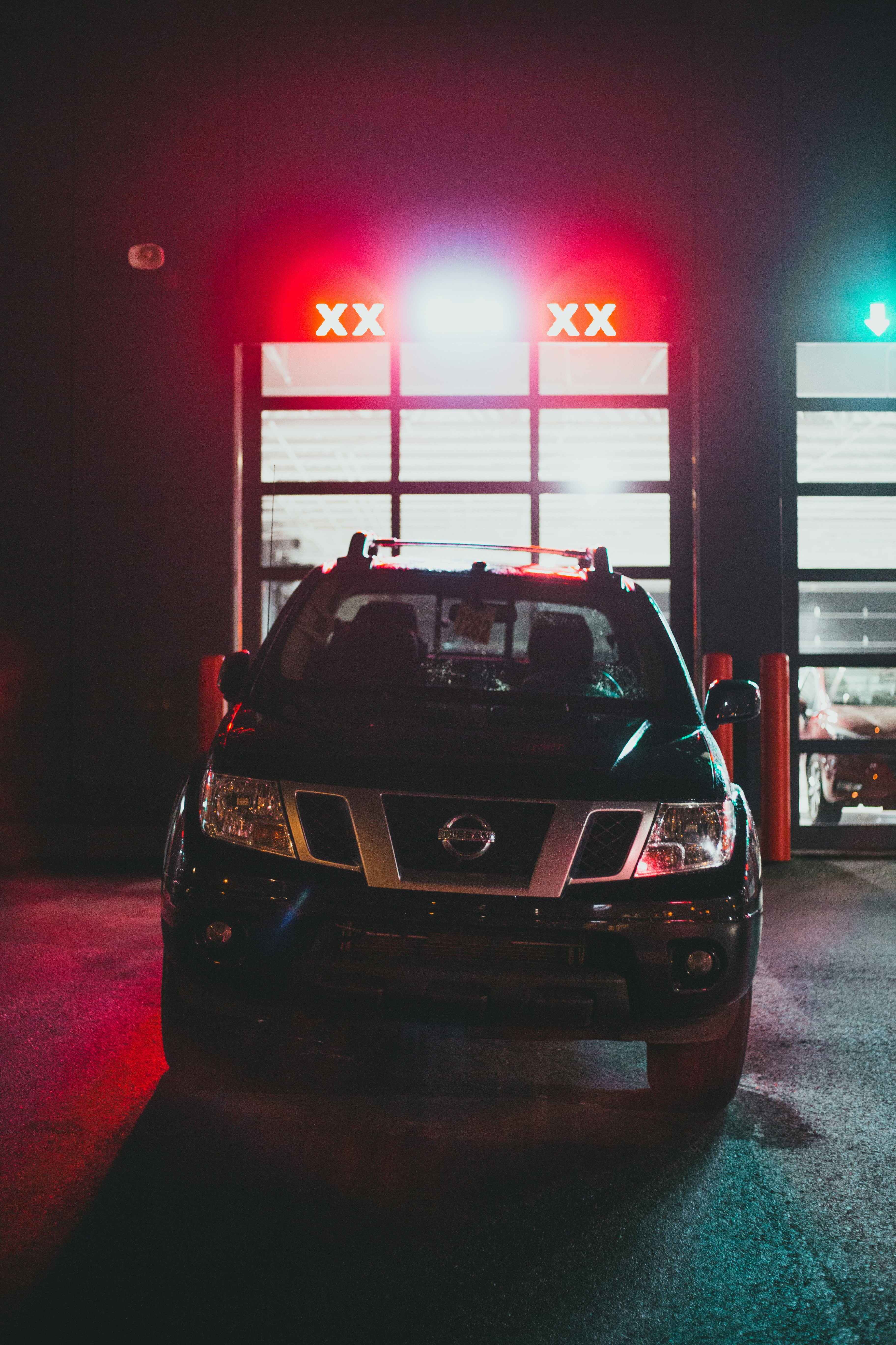 Neon Stop at the Garage: A Nissan Police SUV Under Red and Cyan Lights