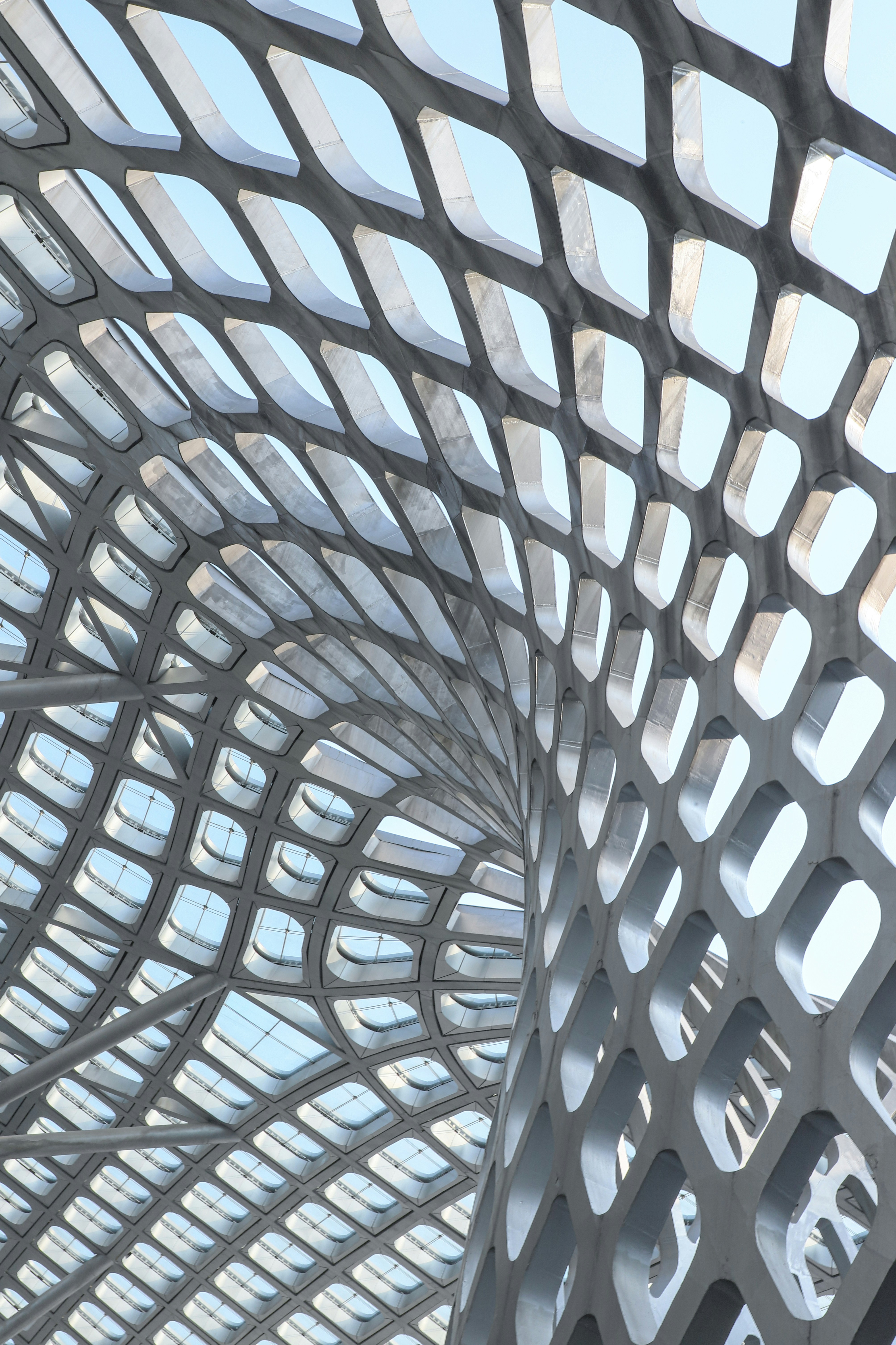 Intricate latticework of a modern architectural canopy, showcasing dynamic curves and interplay of light and shadow.