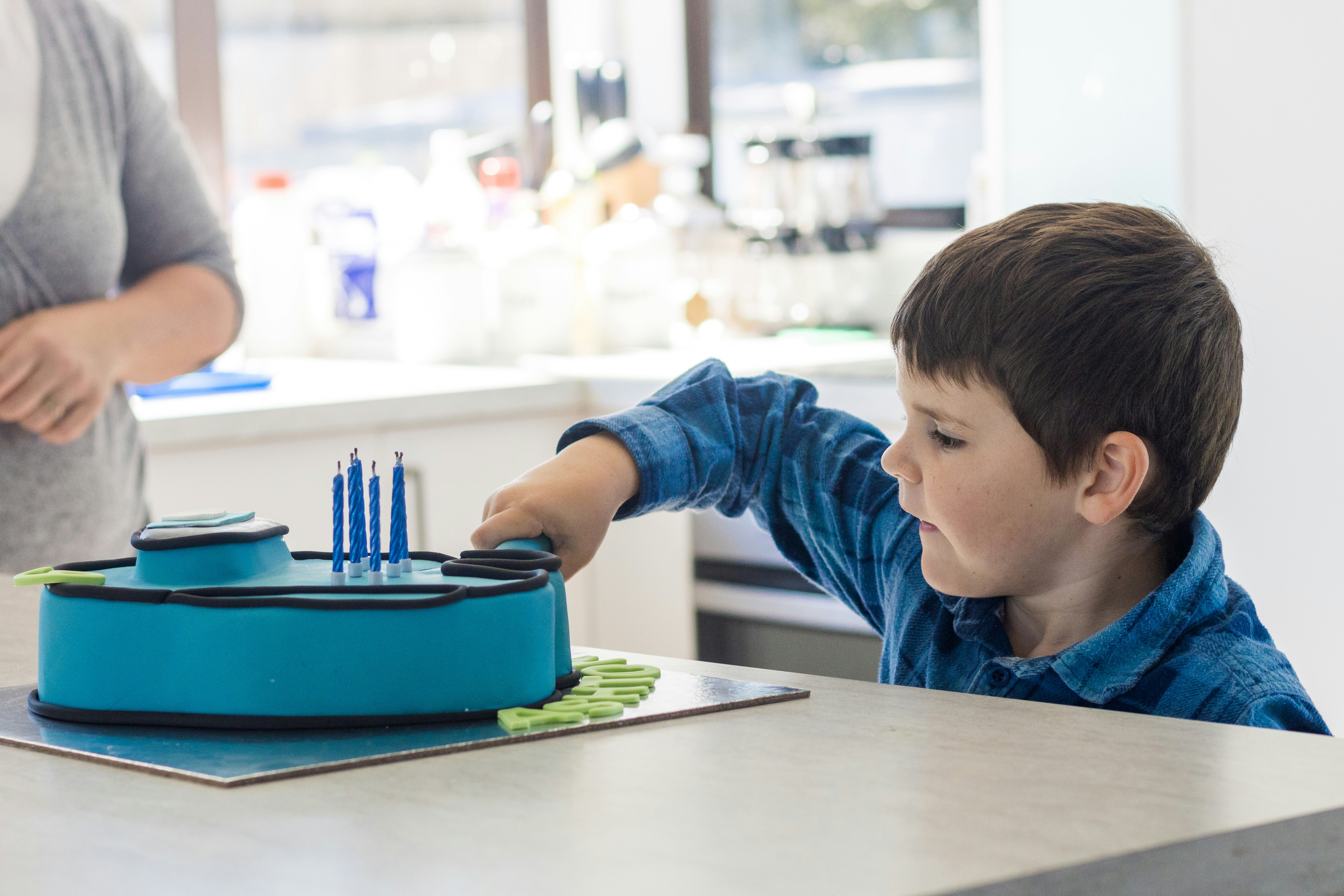 Child at a Cake of Mini Candles: Quiet Focus at a Kitchen Table