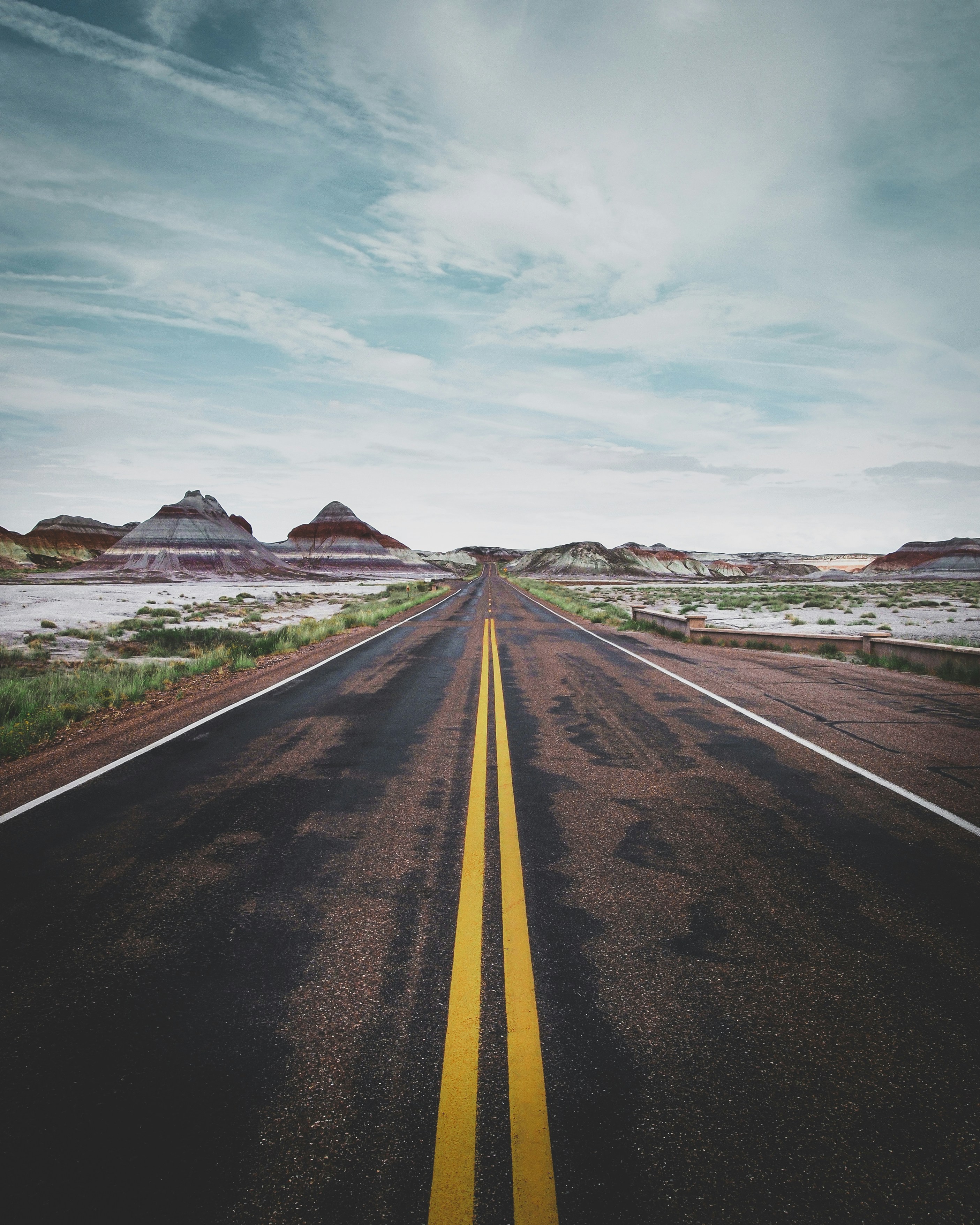 Vanishing Point on a Desert Highway toward Layered Badlands