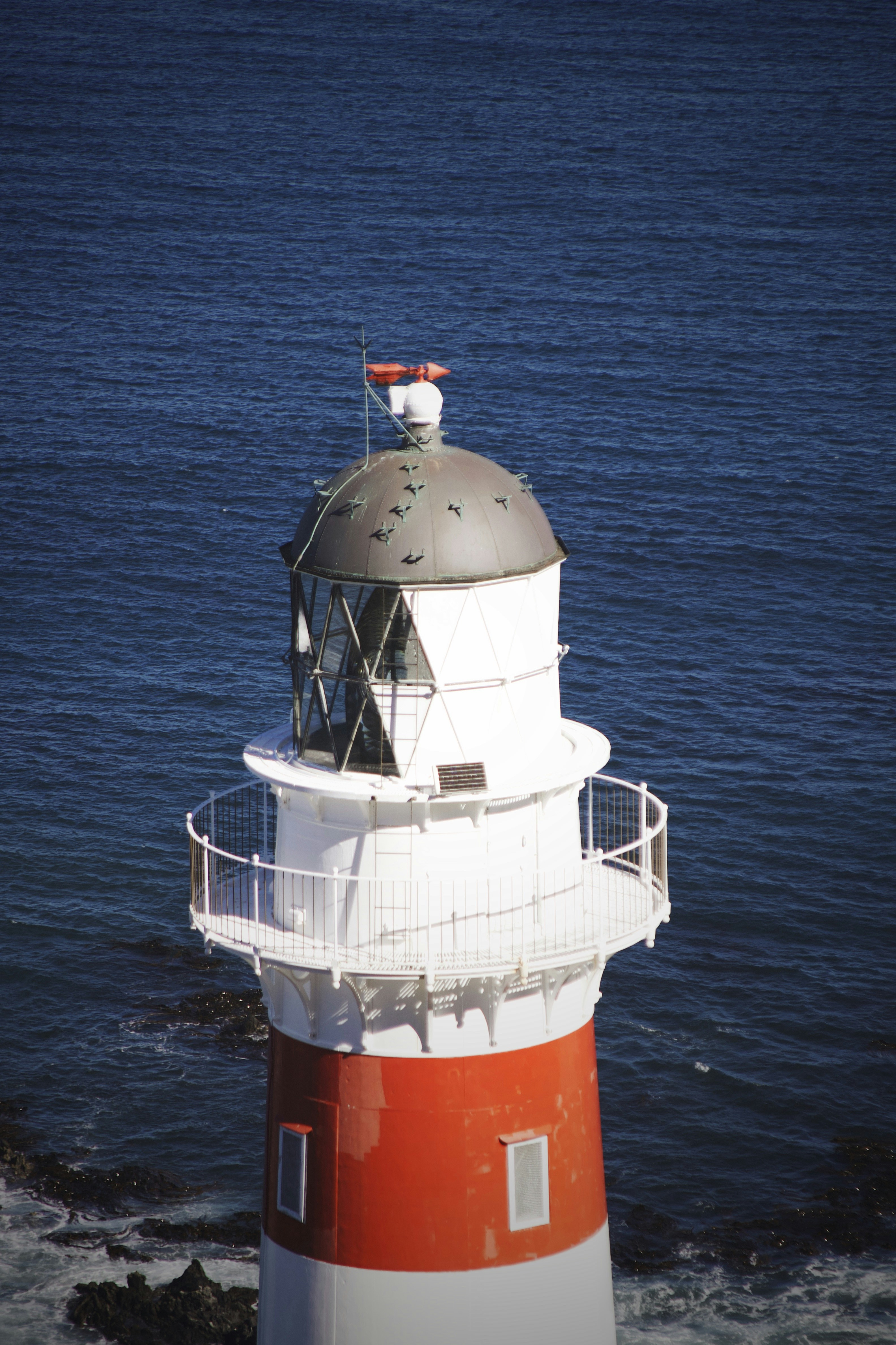 Lighthouse Sentinel: Red-White Tower Rising Over a Deep Blue Sea