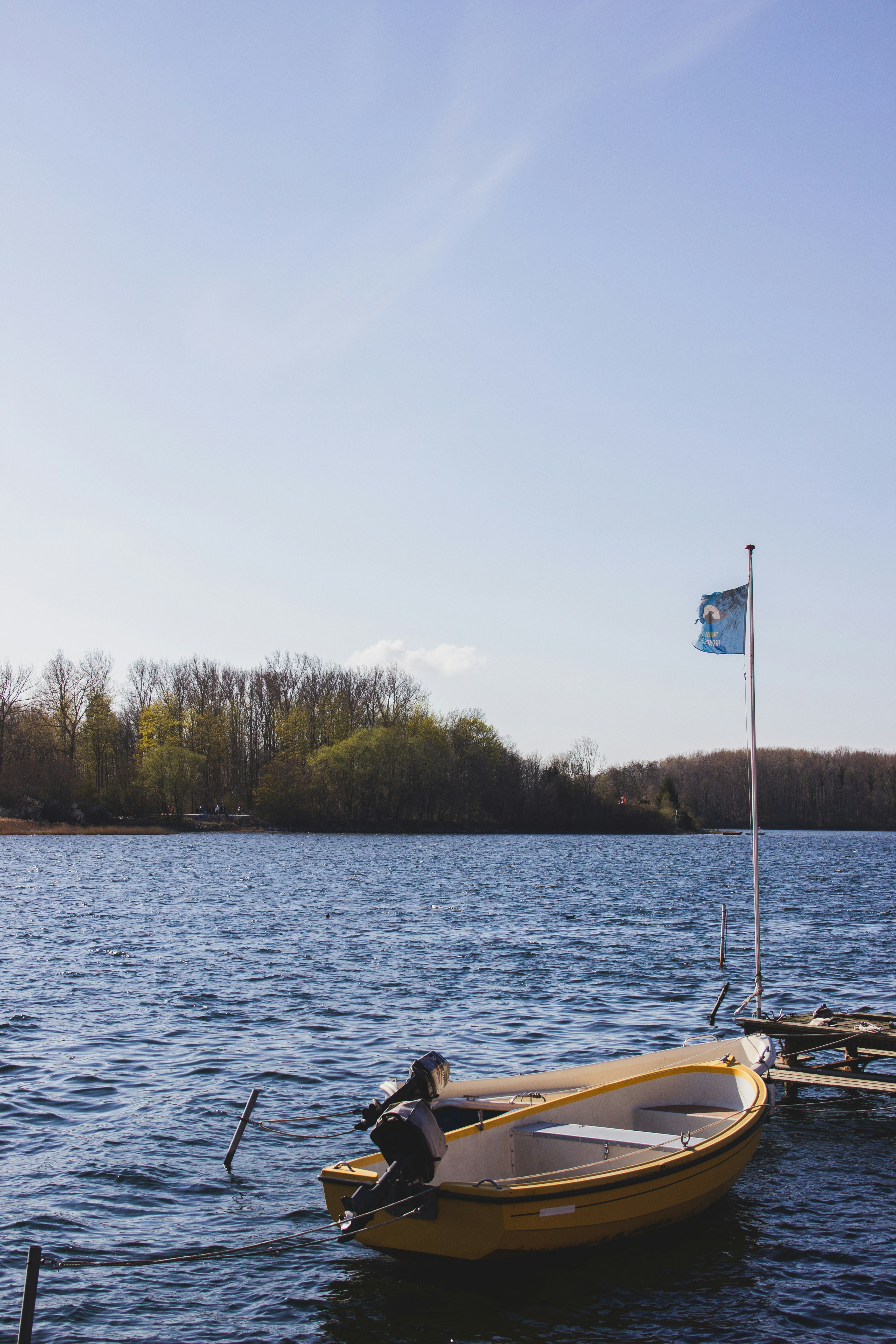 Sunlit Yellow Rowboat by a Quiet Lakeside Dock