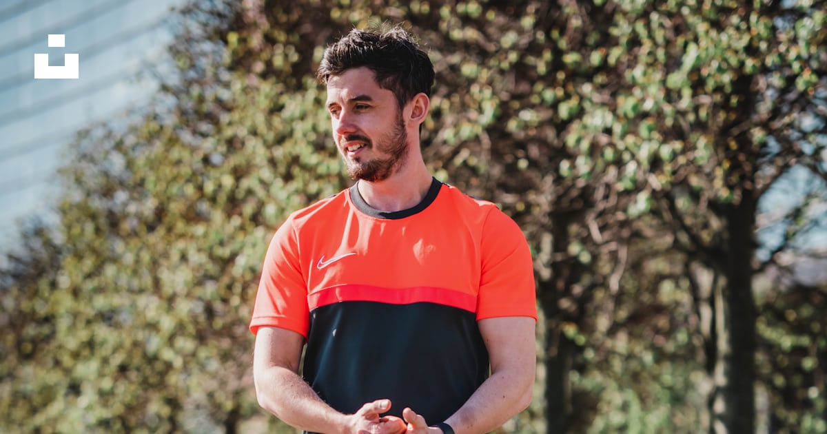 Man In Red Nike Crew Neck T Shirt And Black Shorts Standing On Gray