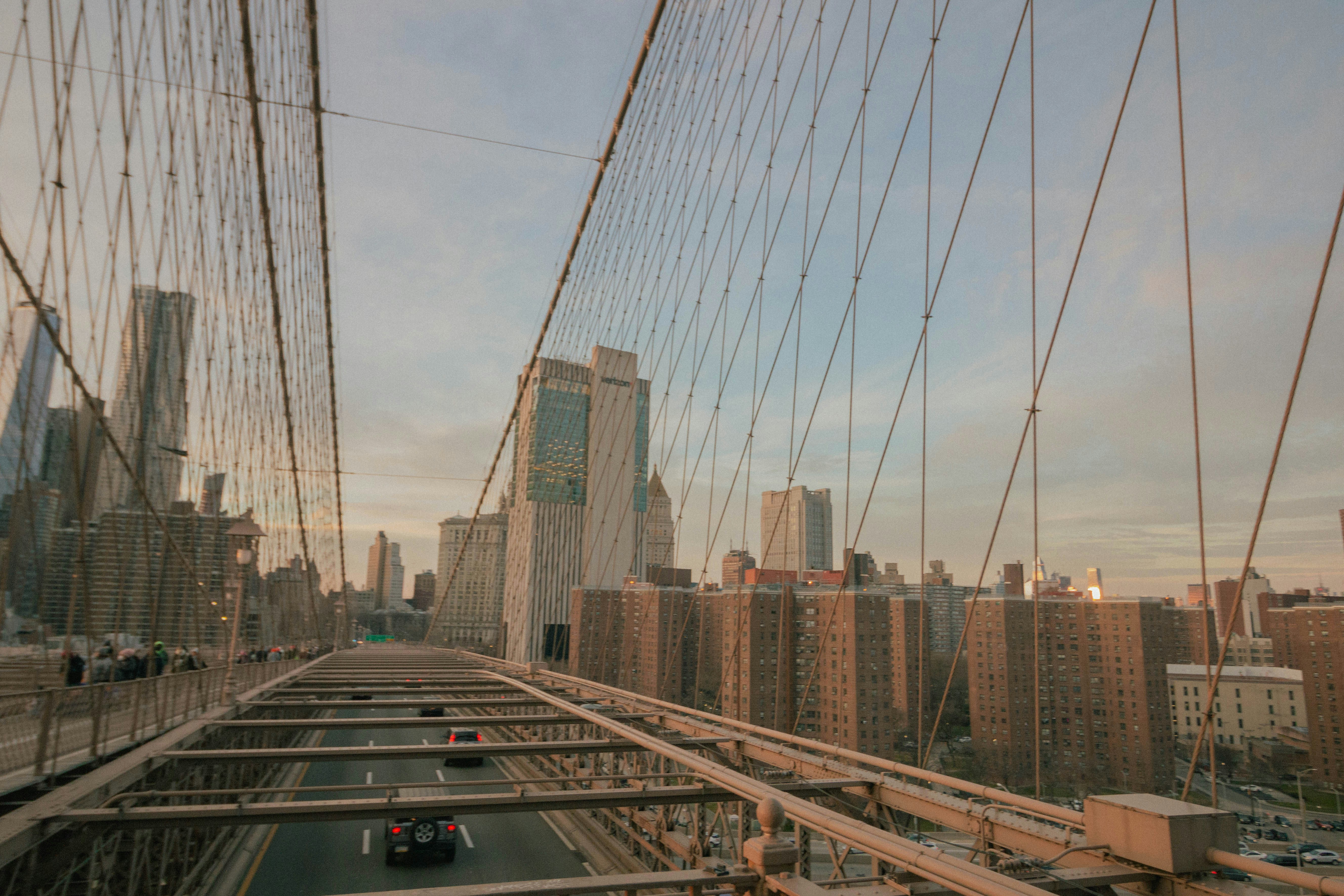 View from the Brooklyn Bridge showcasing the intricate cable structure and the skyline of Manhattan in the background.