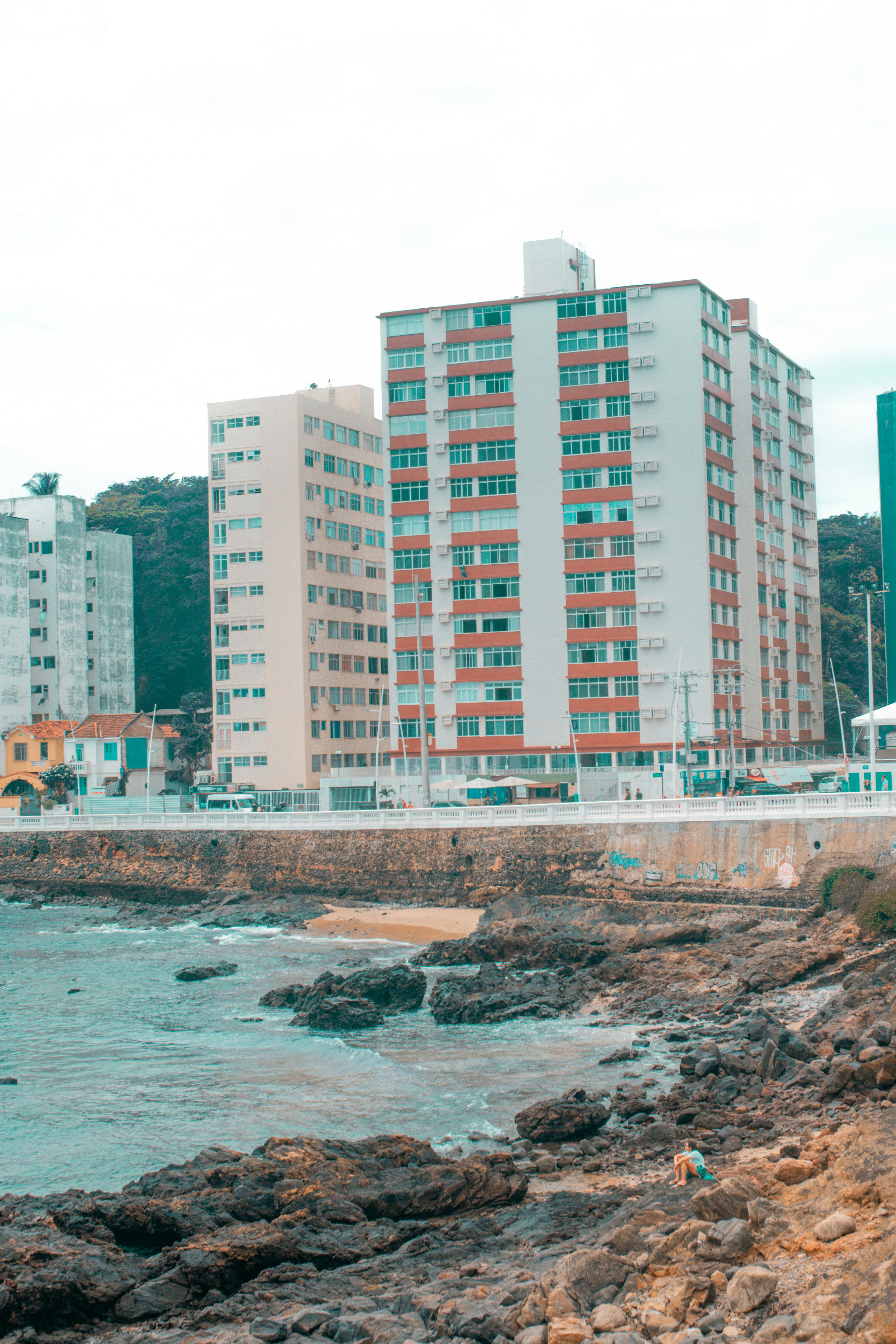 Coastal view featuring modern buildings alongside rocky shores, capturing the blend of urban life and natural beauty.