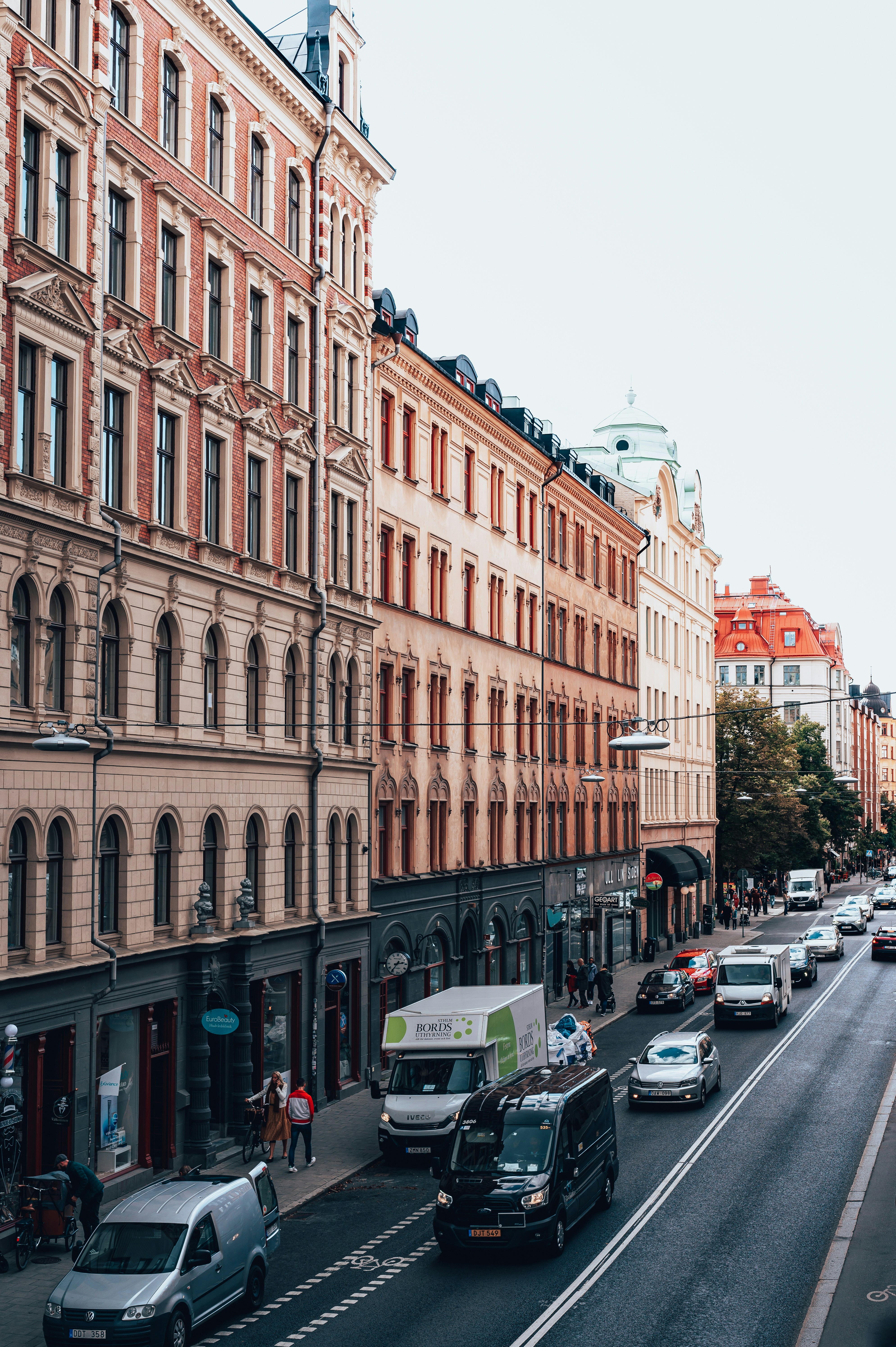 Busy street scene showcasing a blend of historic and modern architecture with vehicles and pedestrians navigating the thoroughfare.