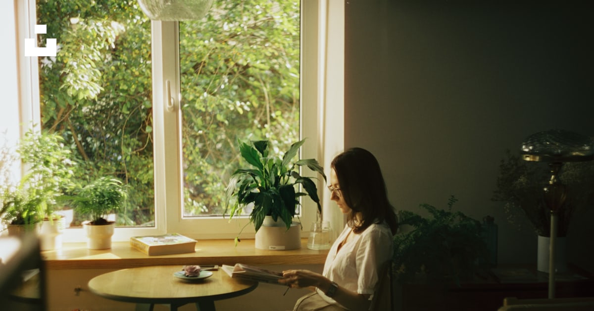 낮 동안 창문 근처 의자에 앉아 있는 하얀 드레스 셔츠를 입은 여자 사진 Unsplash의 무료 아날로그 사진 이미지