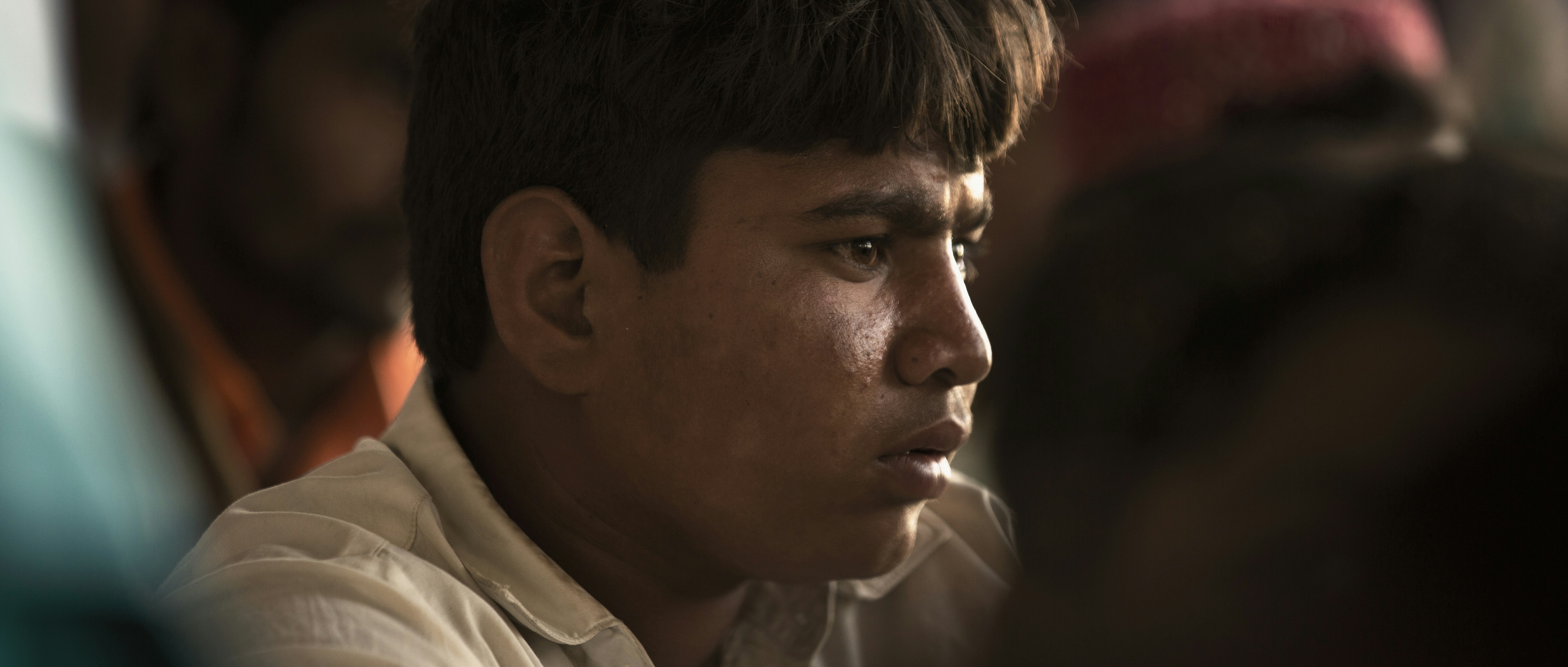 Young man in thoughtful pose, surrounded by soft, warm lighting.