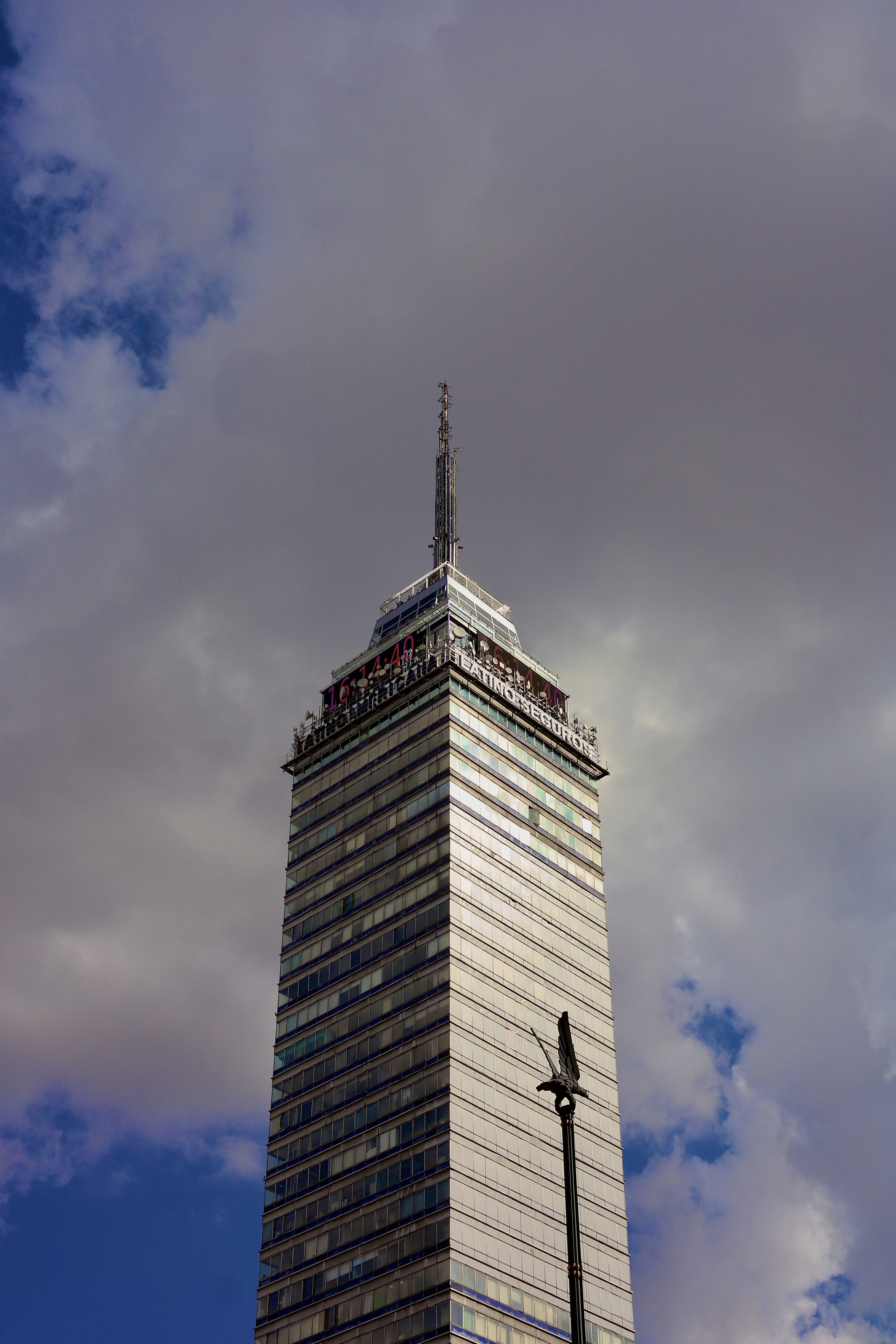 Iconic skyscraper piercing the sky, adorned with reflective glass and a distinctive antenna. The scene captures the interplay of architecture and cloud formations.