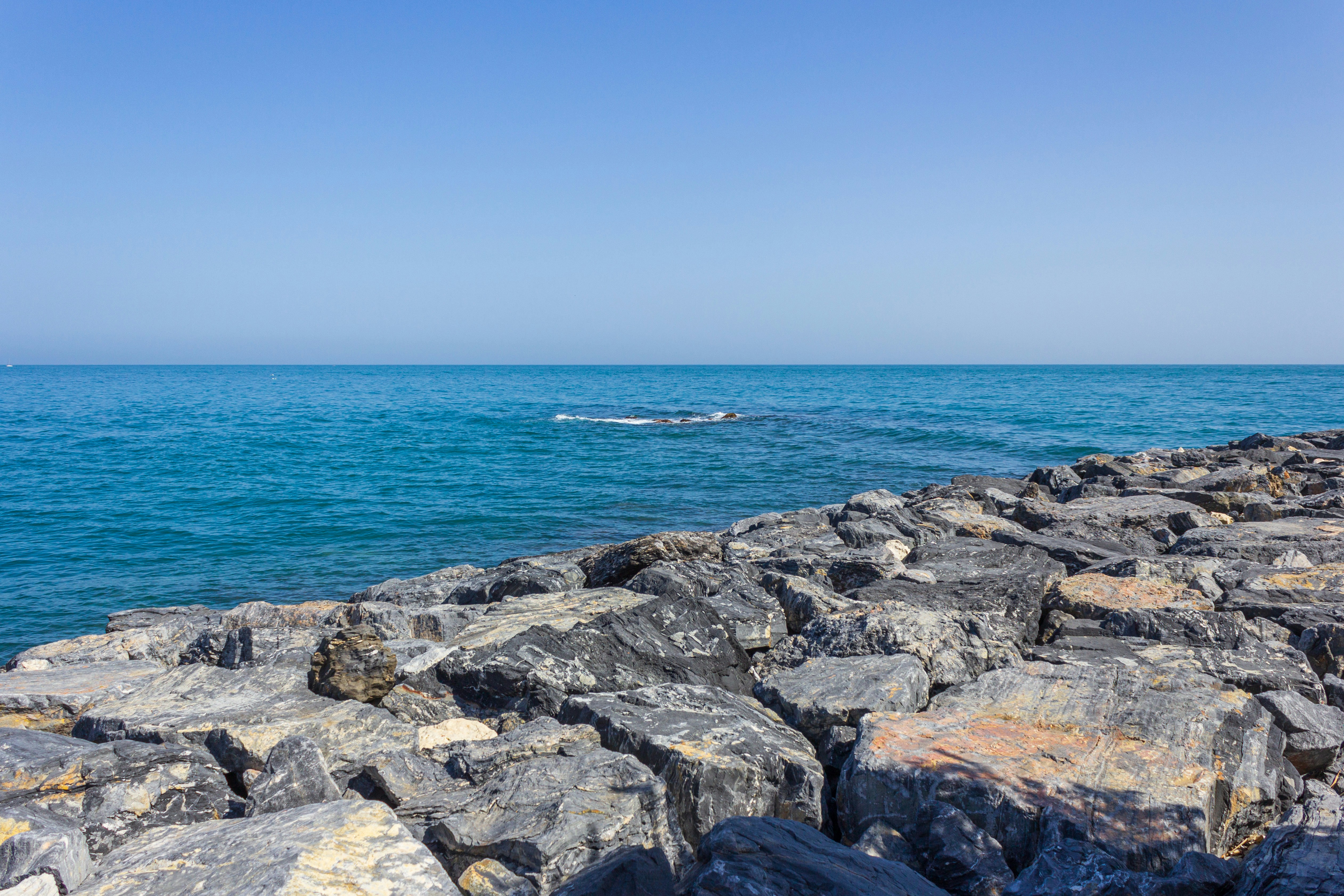 Expansive rocky shoreline extending into a calm, blue ocean under a clear sky.
