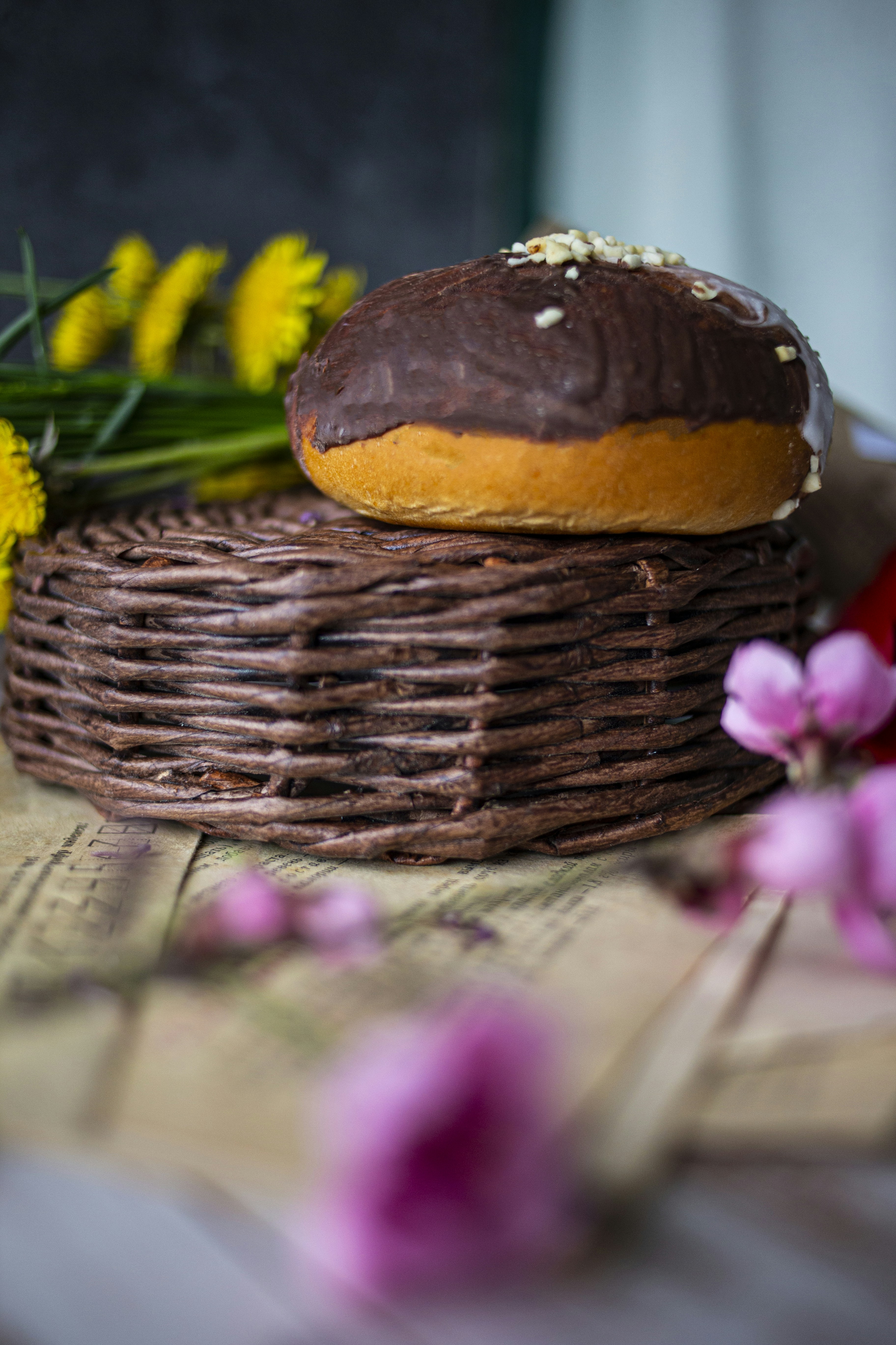 Glazed Doughnut on a Wicker Pedestal, Framed by Spring Blooms