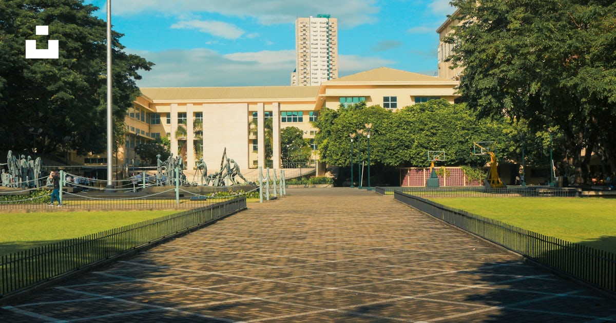 昼間は青空の下、緑の木々のそばに白いコンクリートの建物が建っていますの写真 Unsplashの建物の無料画像