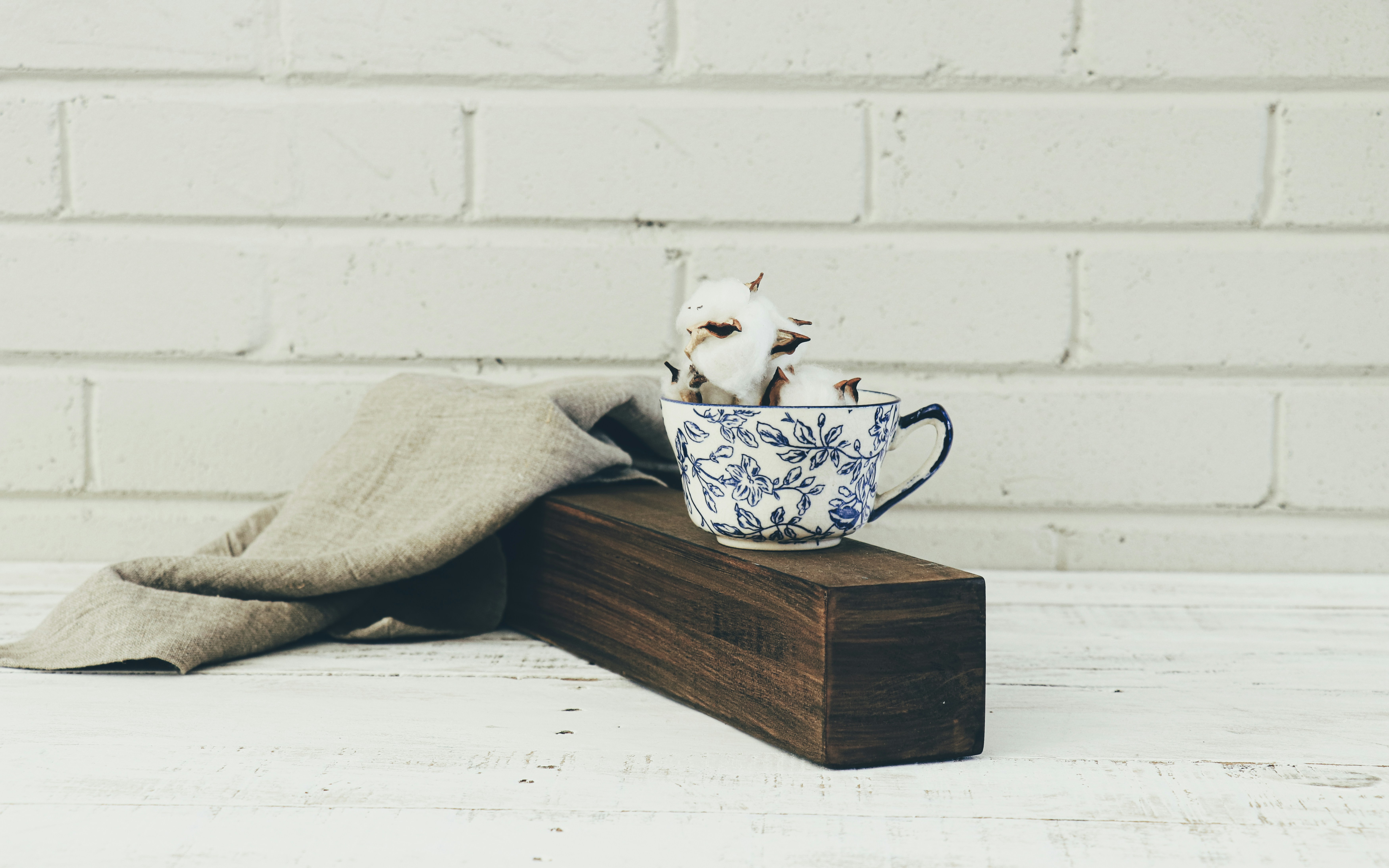 Delicate teacup on wood with white brick background.