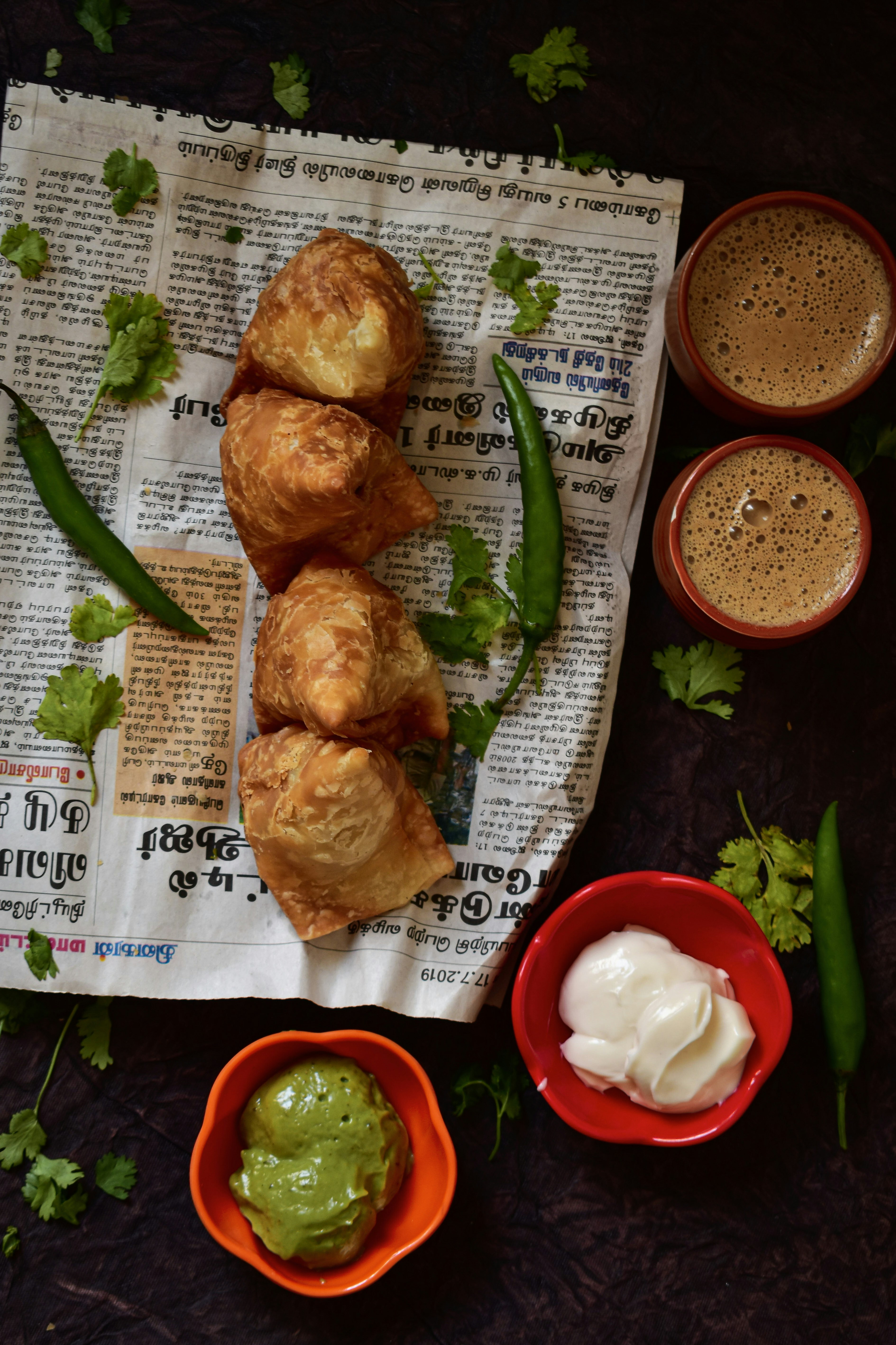 Crescent Carousel: croissants on ink-stained newspaper with chilies, cilantro, and dips