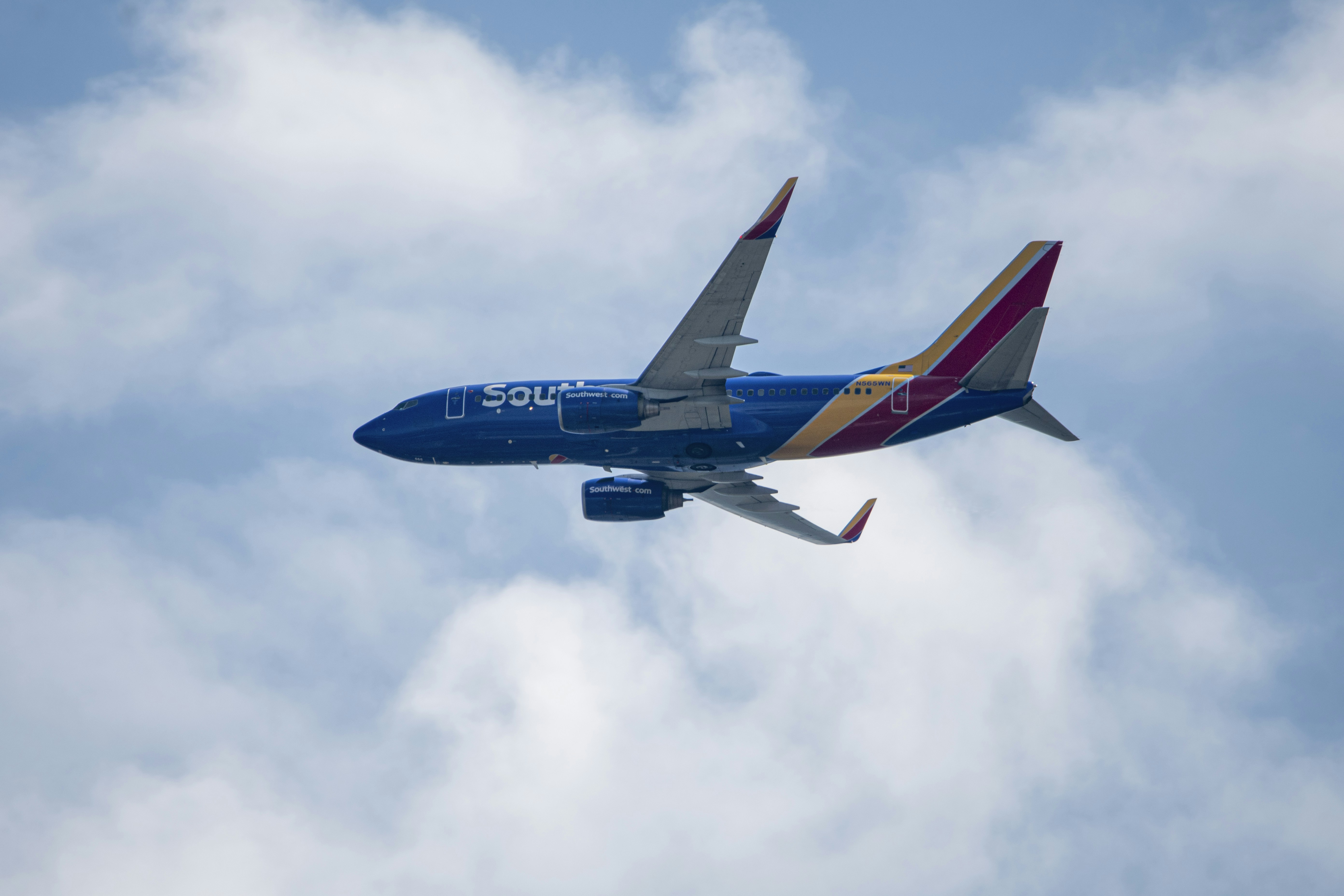 Cobalt Arrow in a Cotton Sky: A Southwest Jet Glides Through Patchy Clouds