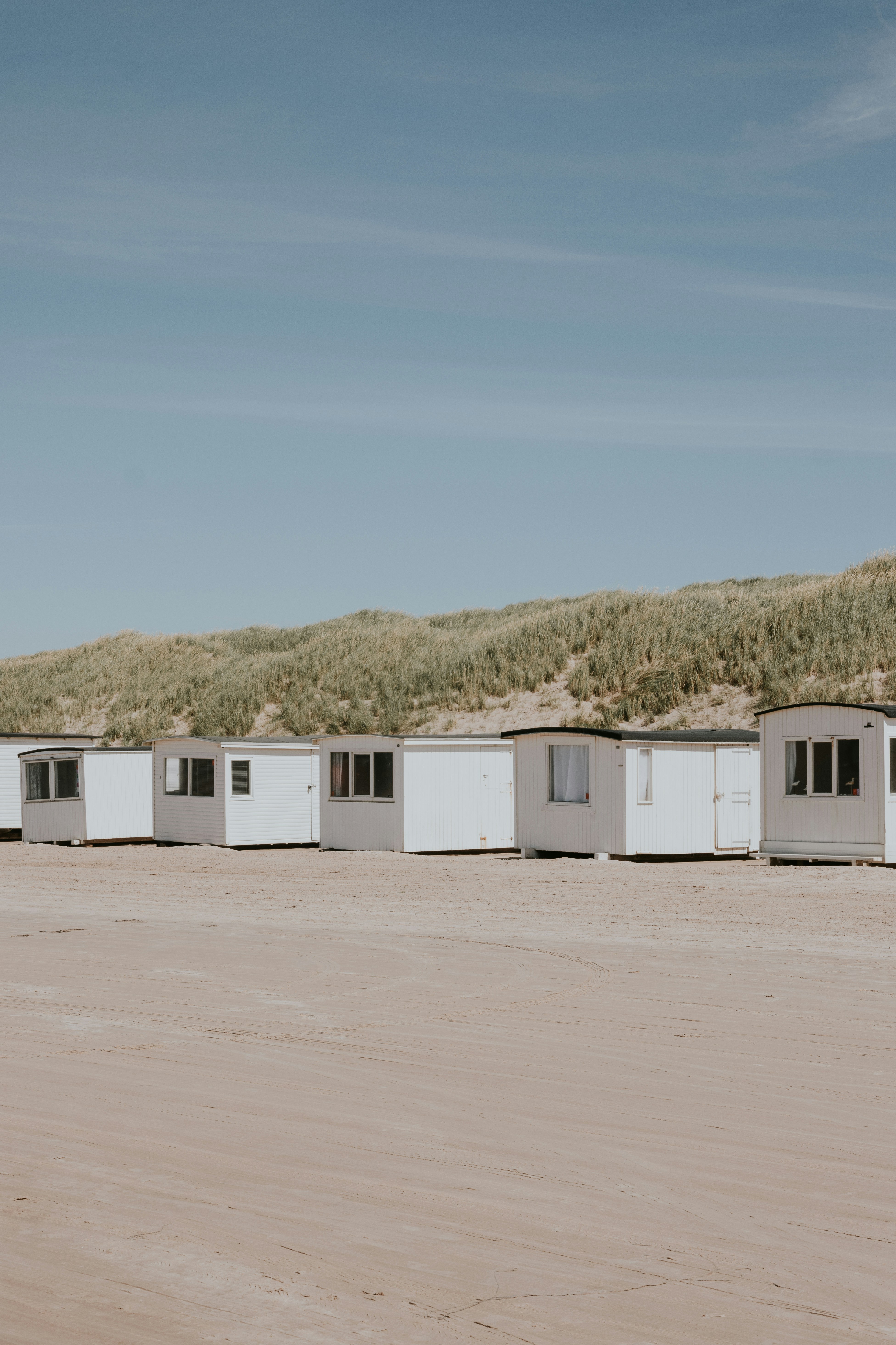 Line of White Beach Huts Along a Wind-Washed Shore