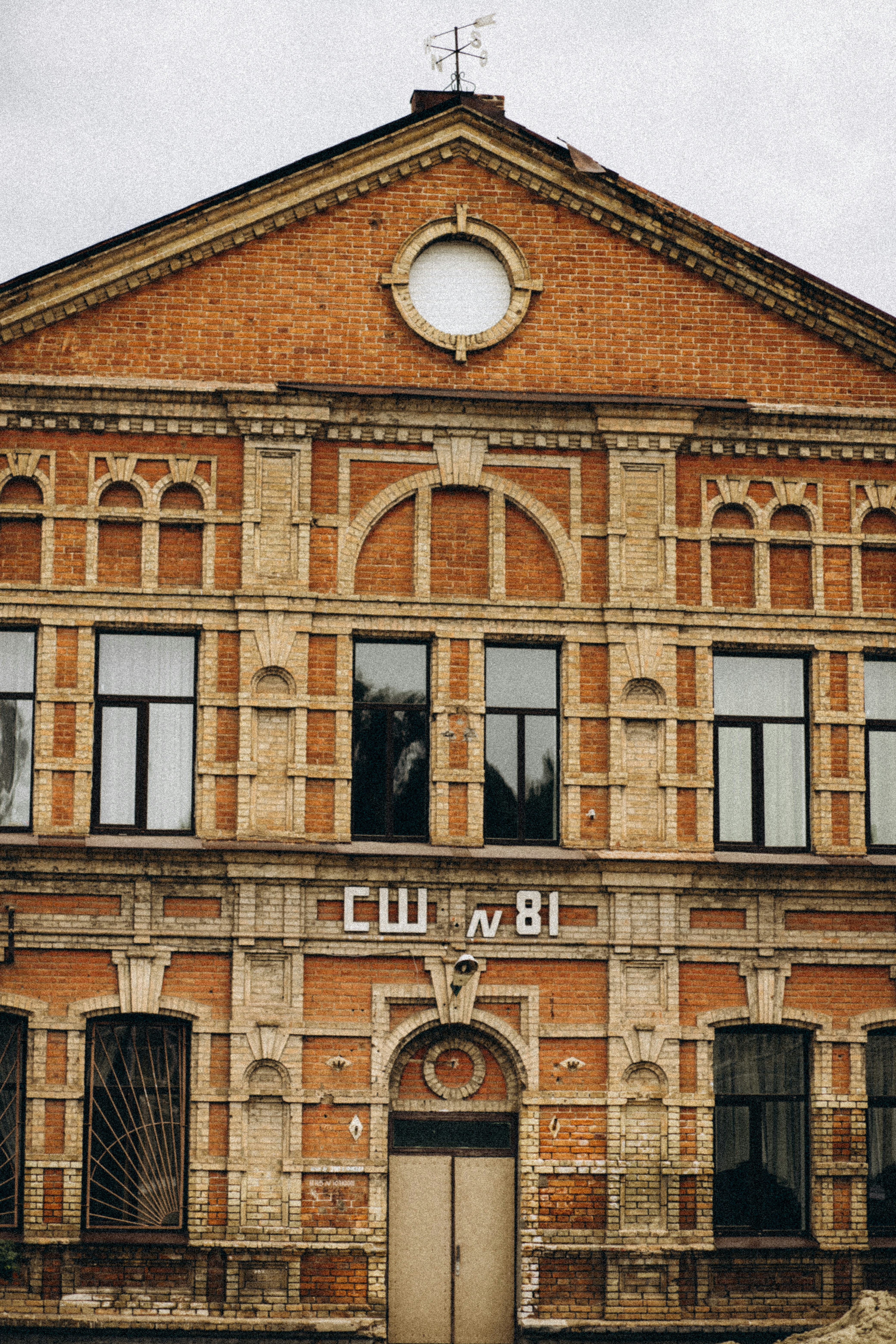 Brickwork Echoes: A historic facade with arched windows and a circular motif