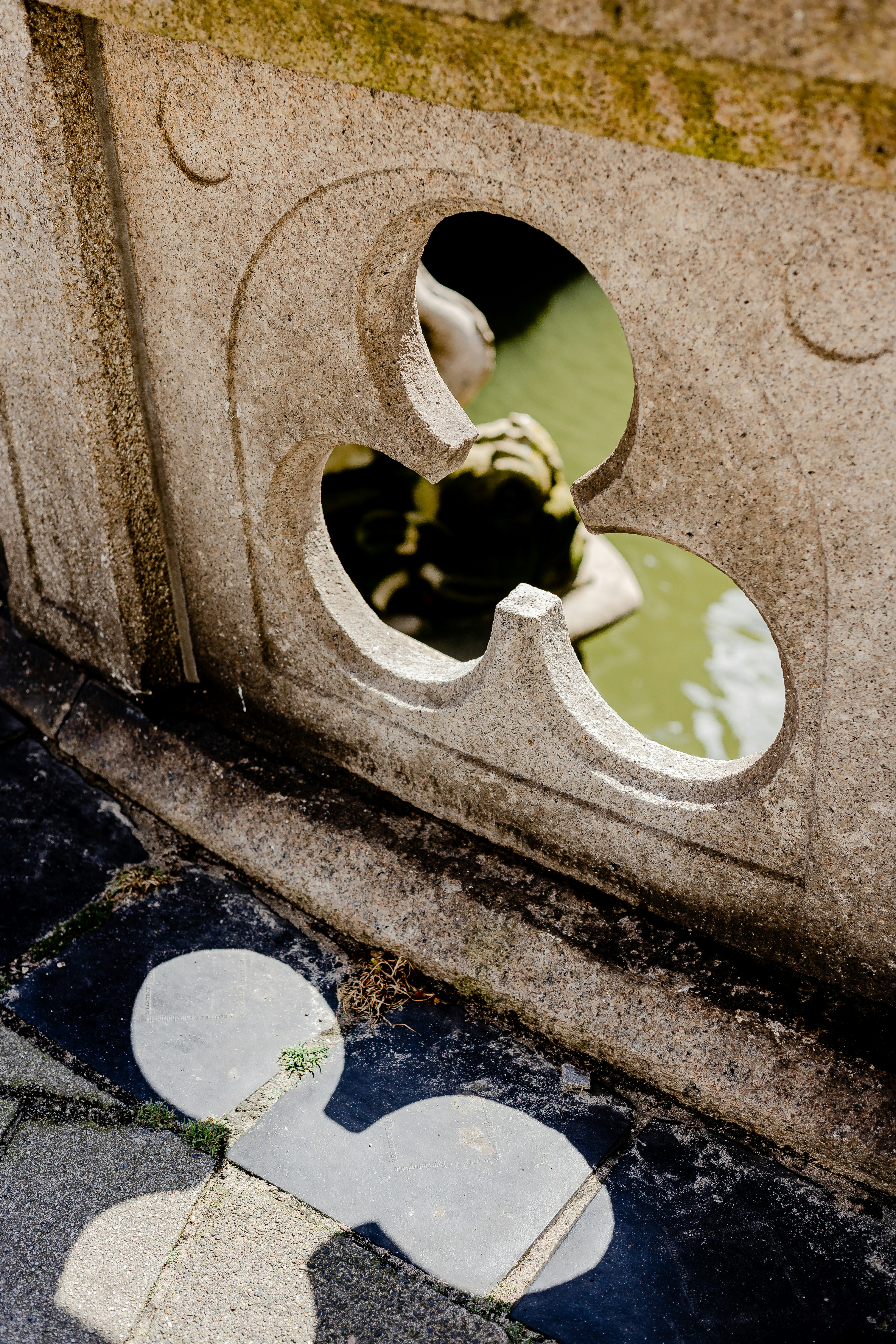Quatrefoil Frame: Weathered Stone Over a Quiet Canal