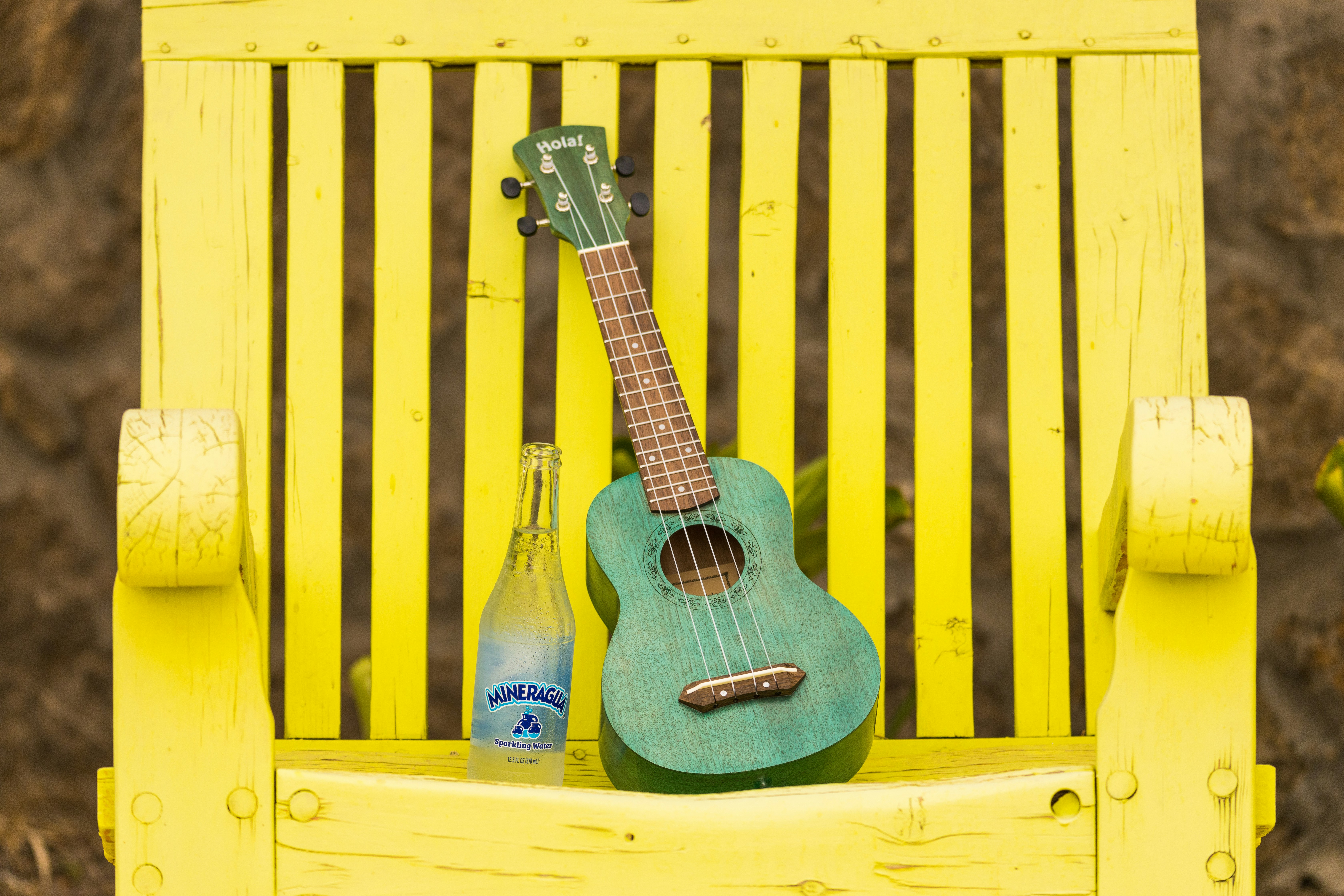 brown acoustic guitar on yellow wooden fence