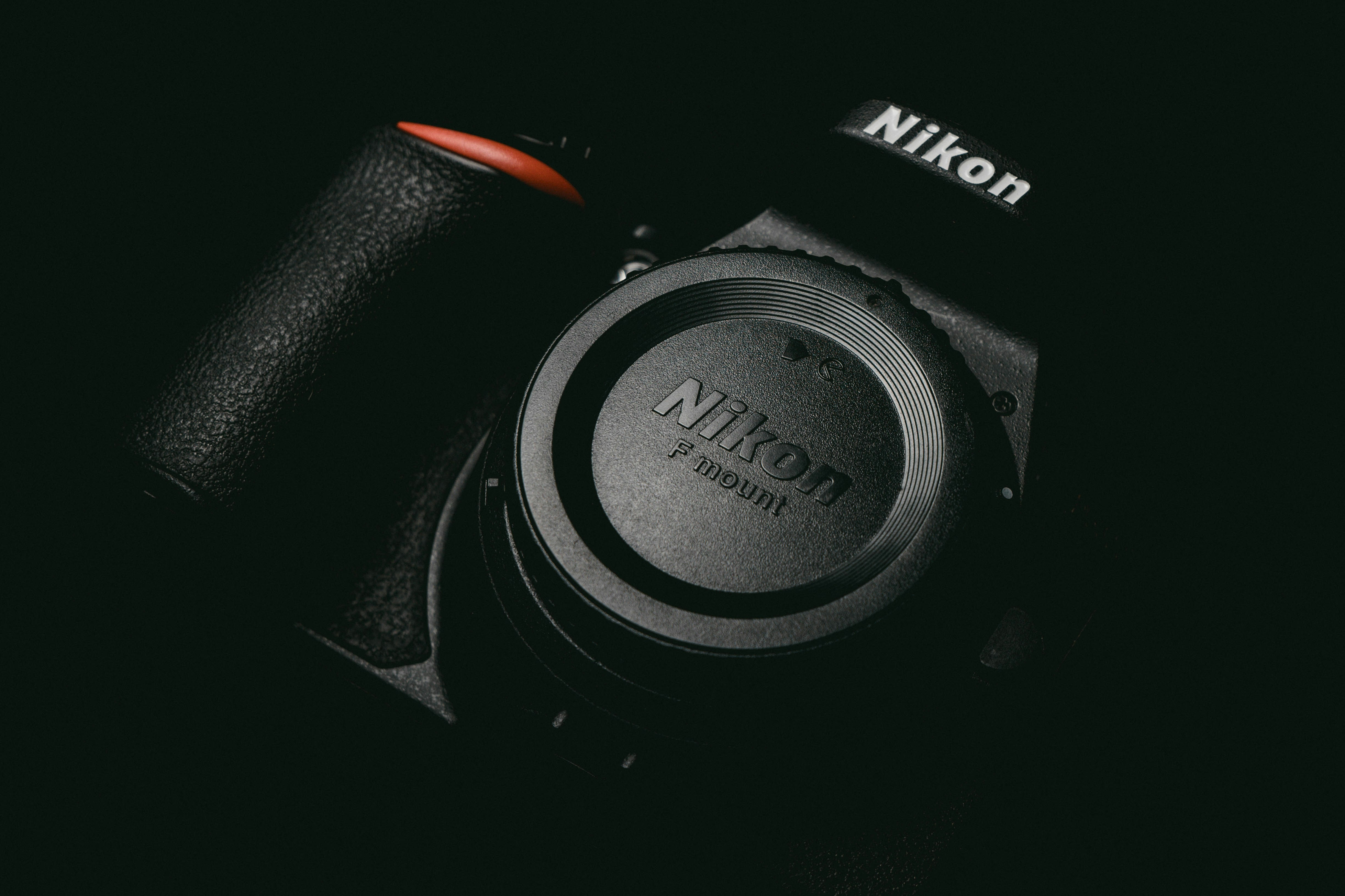 Close-up of a Nikon lens cap resting on a dark surface, highlighting its texture and branding.