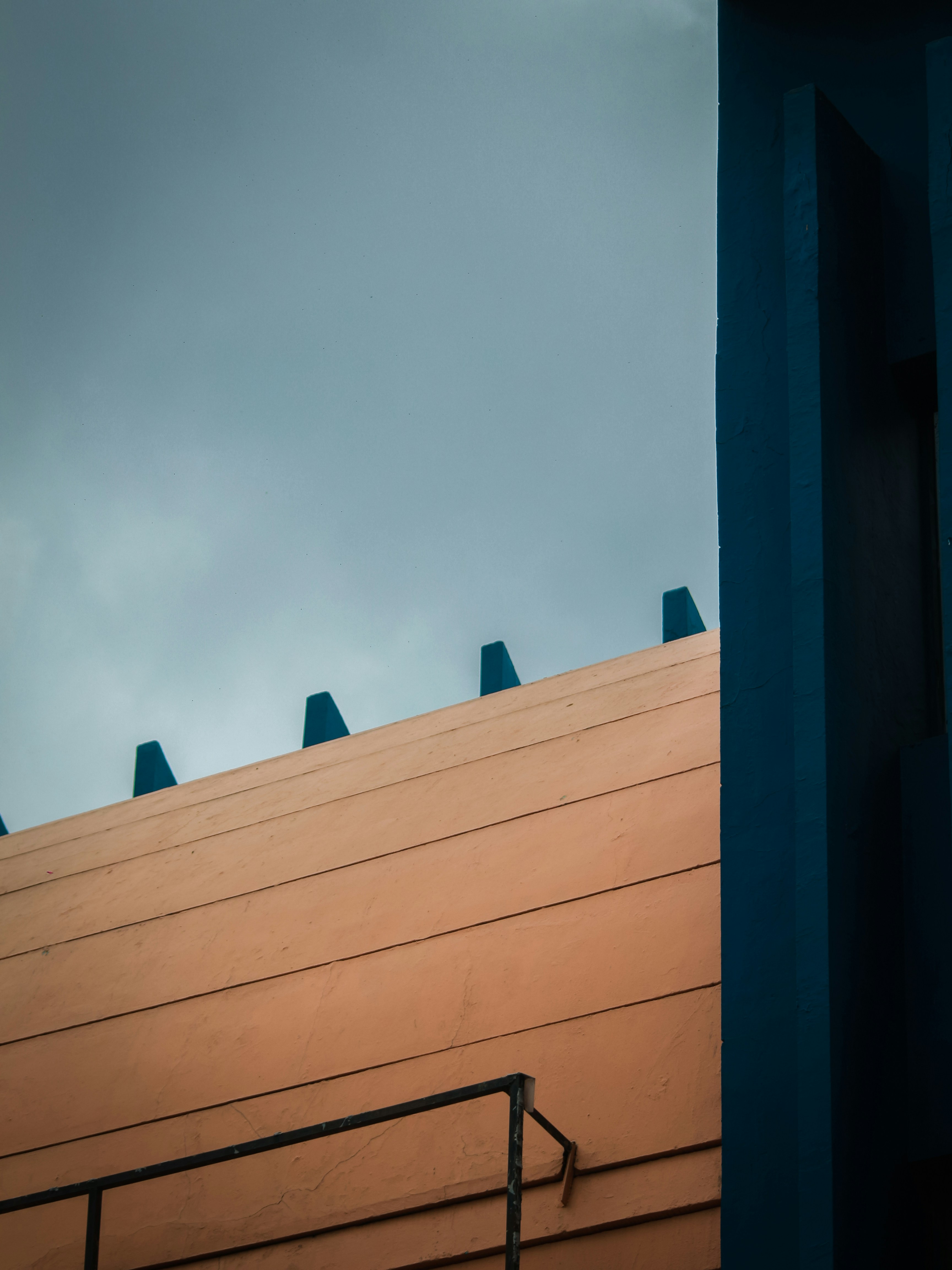 Angular building facade featuring a blend of orange and blue tones under a moody sky.