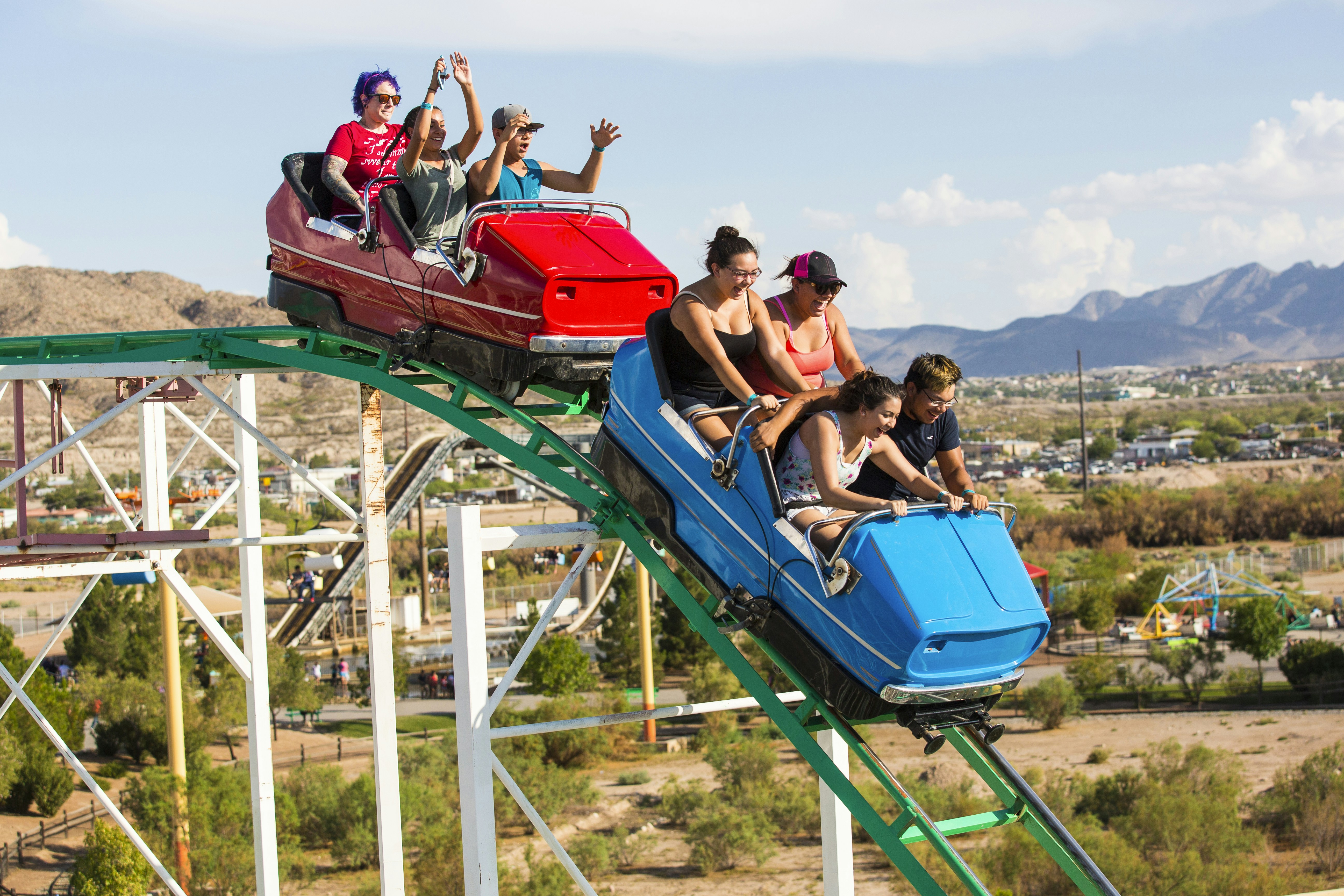 Riders descend down a roller coaster. | 2 women sitting on blue hammock during daytime